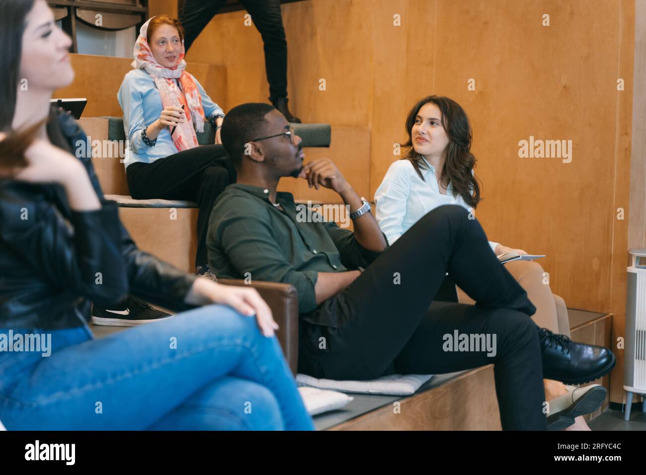 Girl looking back at her colleague talking during presentation at work ...