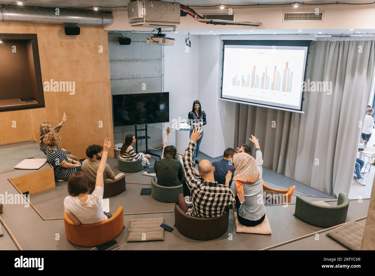 Young and beautiful business woman presenting a sales graph to a ...
