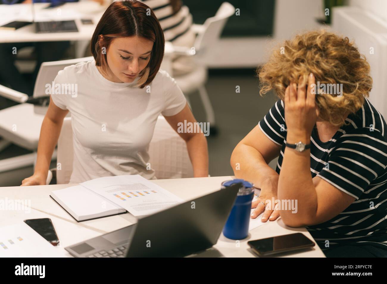 Two women planning and looking at a graph while working in the office ...