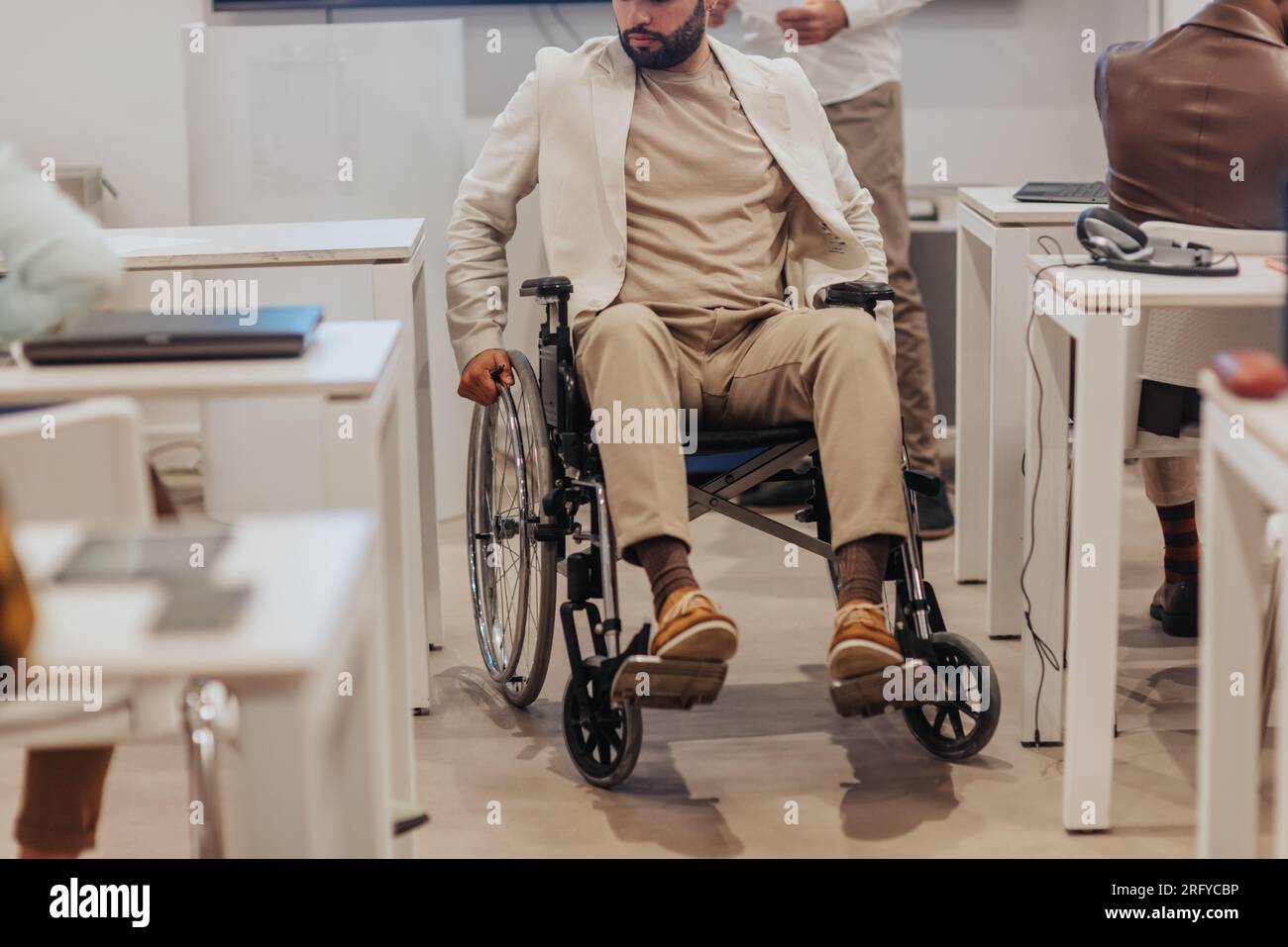 Handicapped business coach rolling wheelchair wheel back to his place ...
