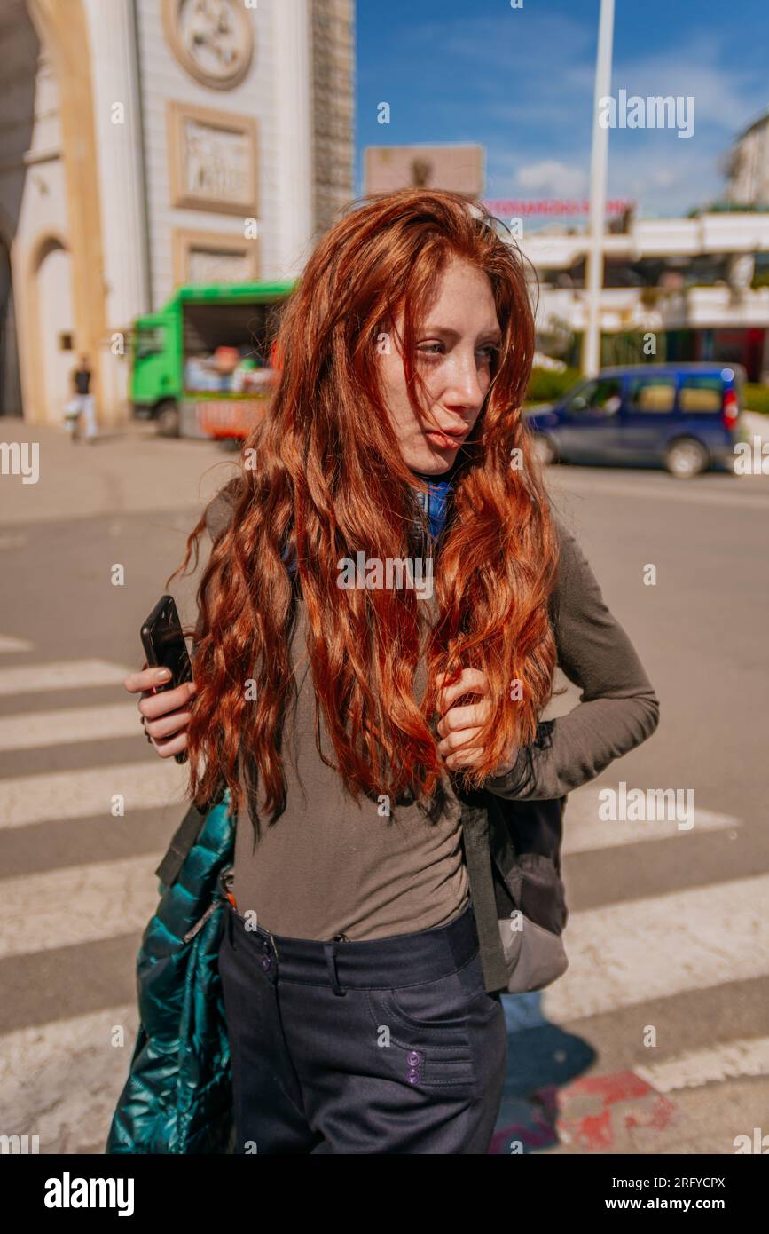 Female ginger tourist hanging out in the city with backpack on. She is ...
