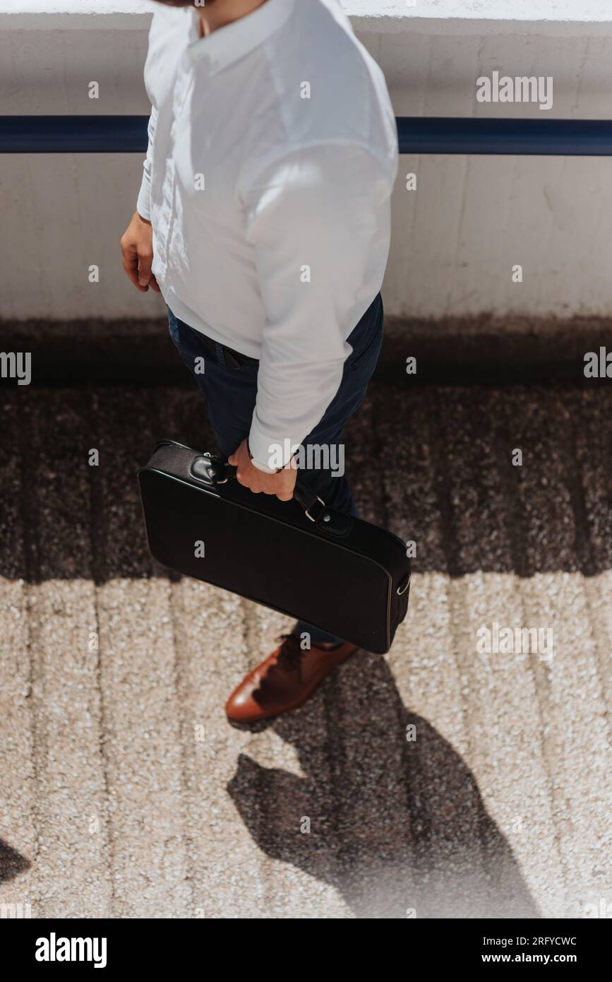 Formal professional businessman outside in the sun holding a briefcase ...