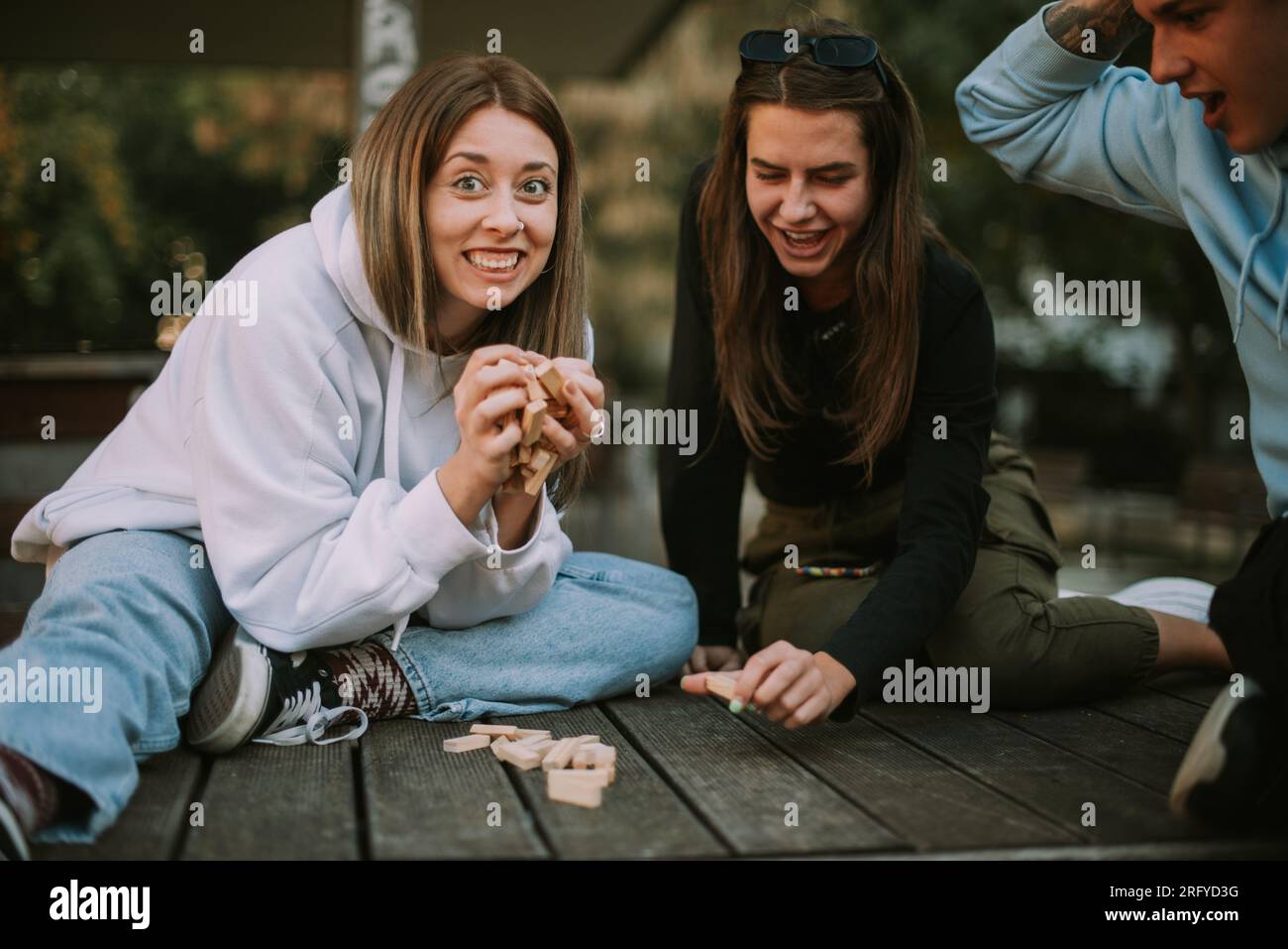 Close up of blonde girl holding wooden jenga in her hands while sitting ...
