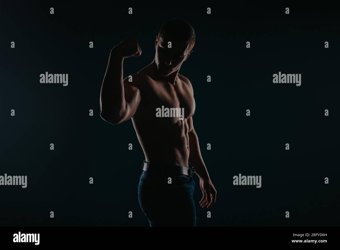 Well-built and charming man standing in front of a dark background and ...