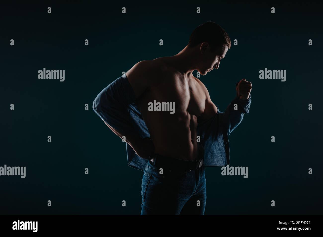 Well-built and attractive man standing in a dark room and flexing his ...