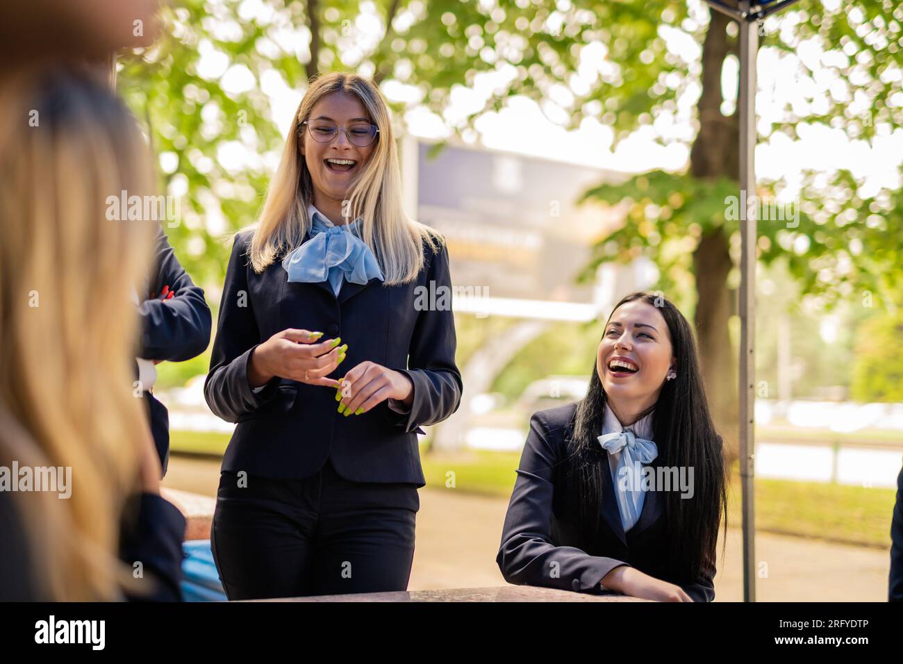 Two young beautiful and charming university students laughing outside ...
