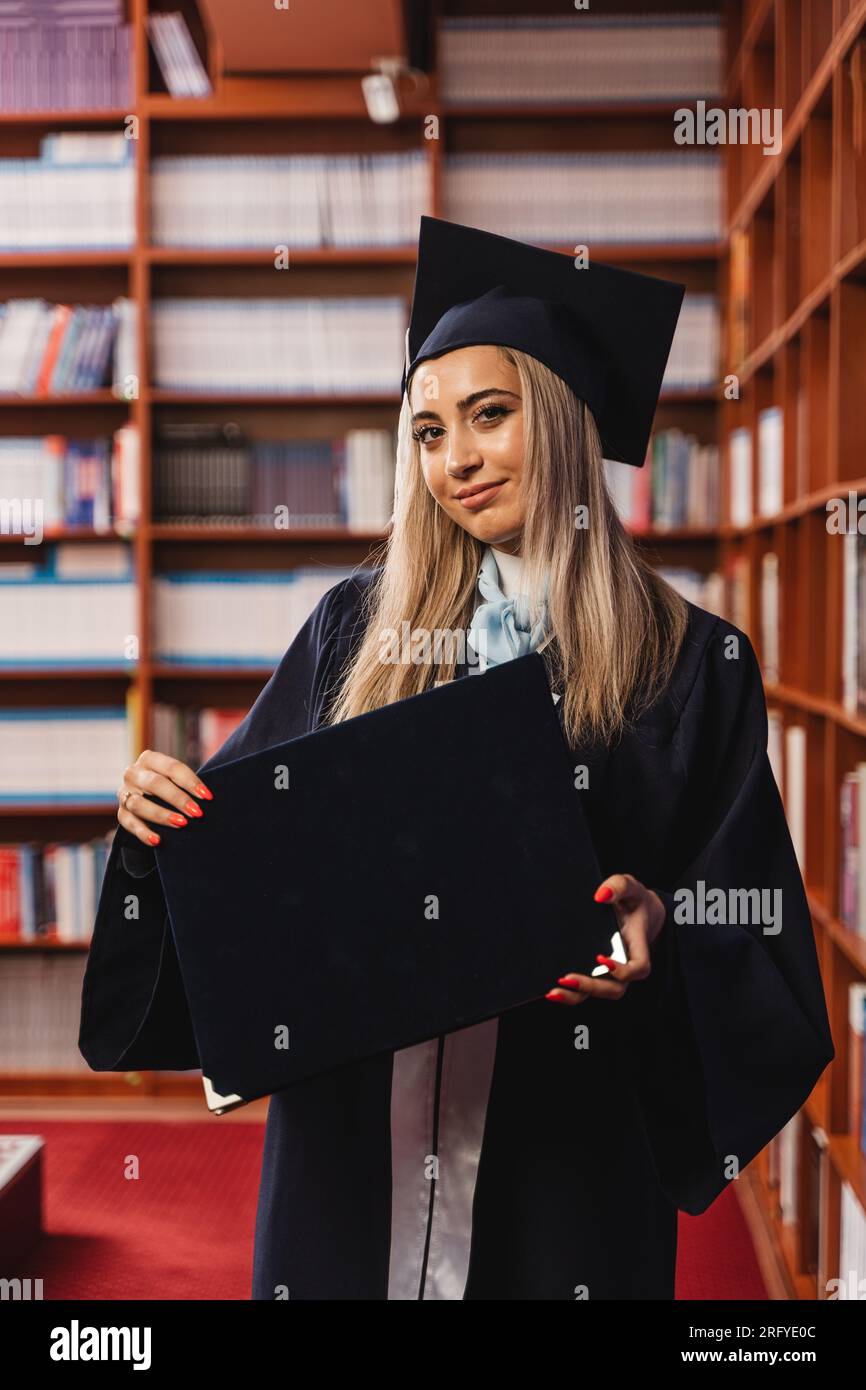 Young and pretty girl holding her bachelor's degree while wearing her ...