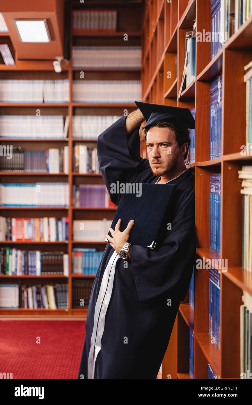 Young graduate looking angry and stressed while holding his degree ...