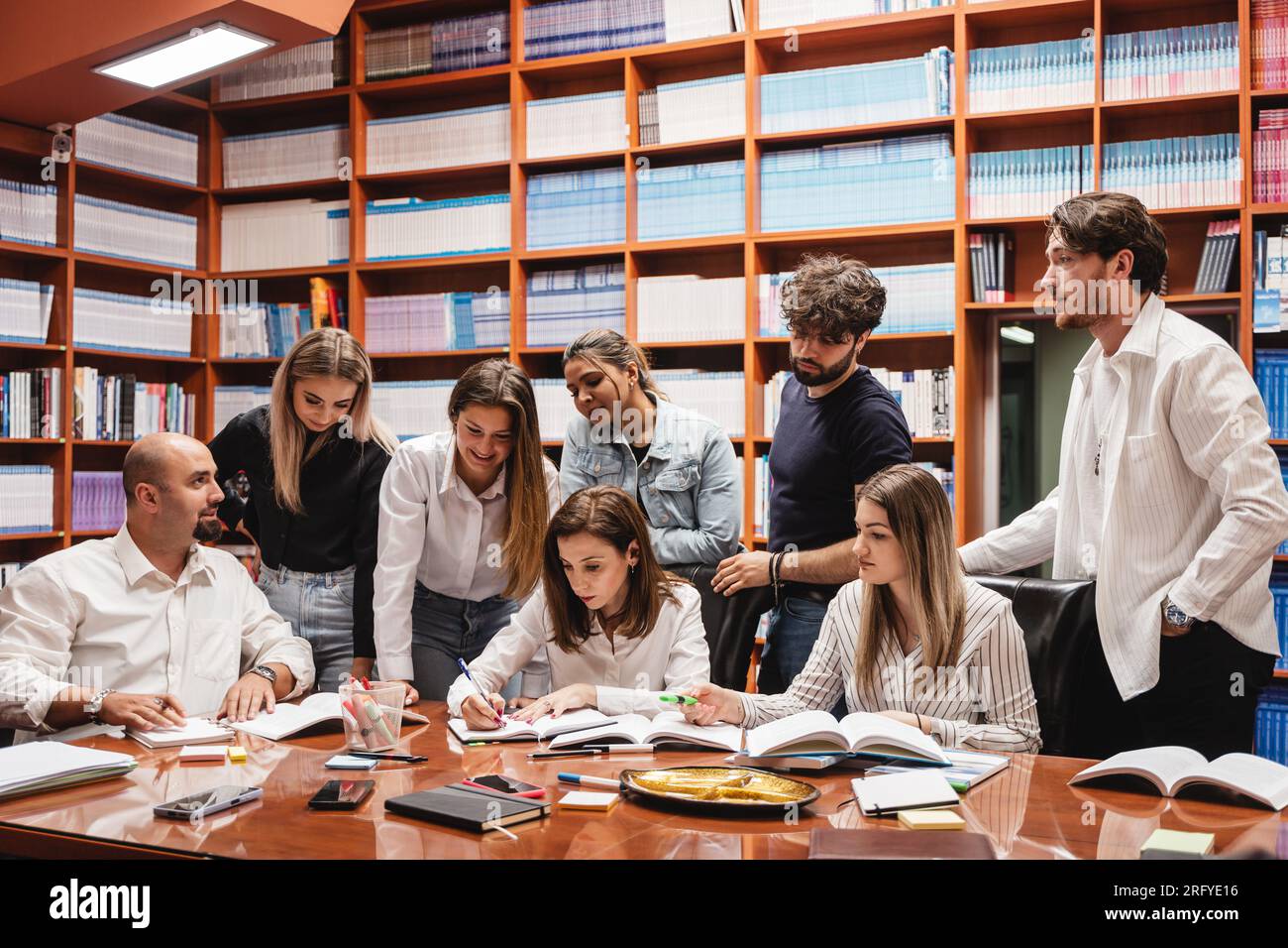 Two professors explaining and talking to a young group of students in ...