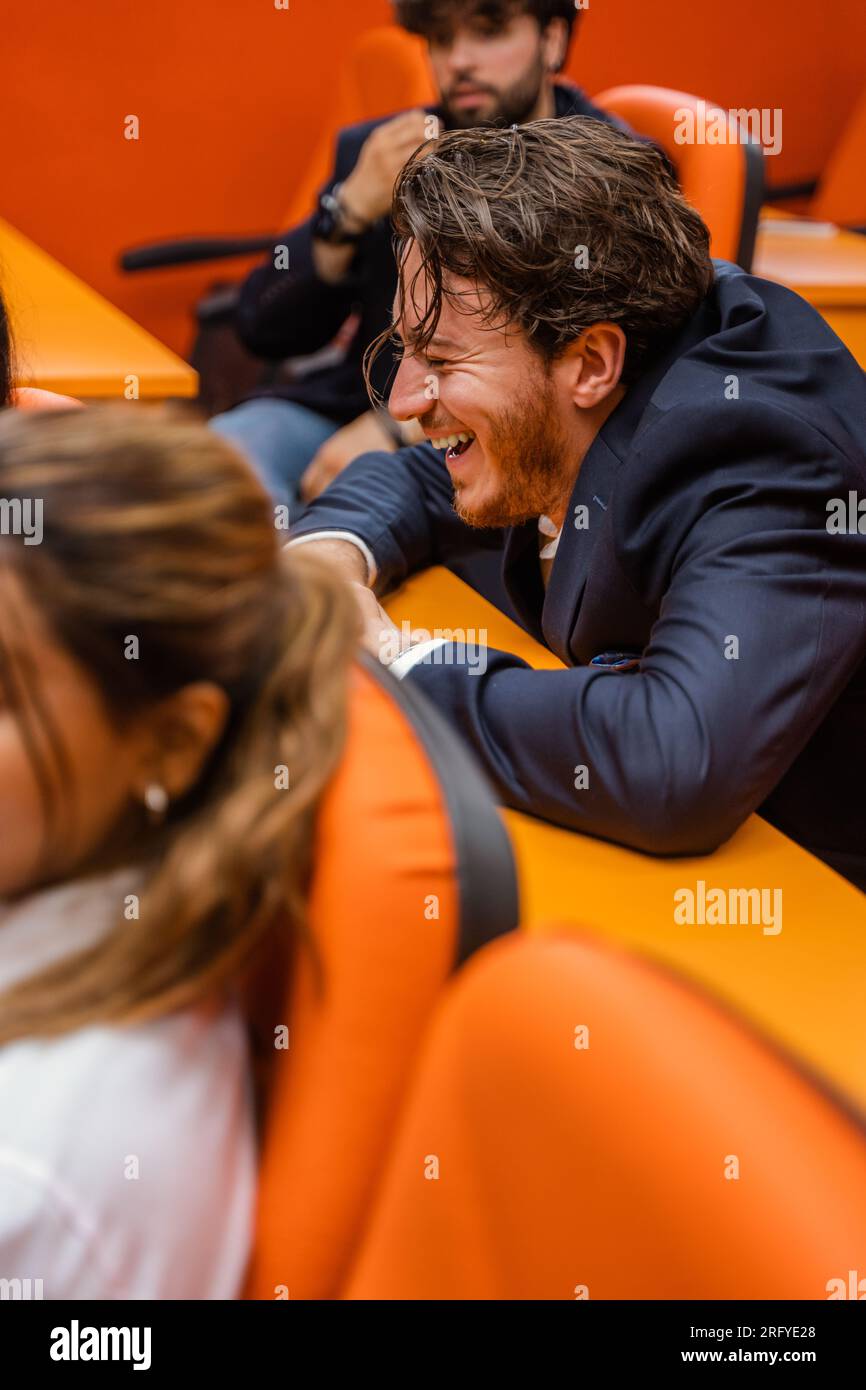 Joyful student laughing while sitting and listening to a lecture in a ...