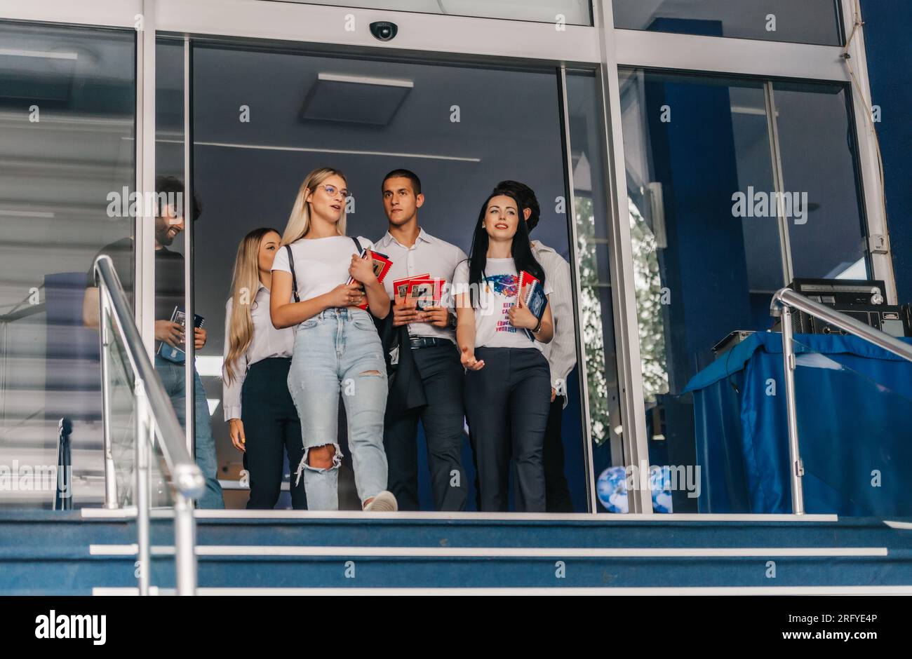 A group of students exiting their college with their notebooks in their ...