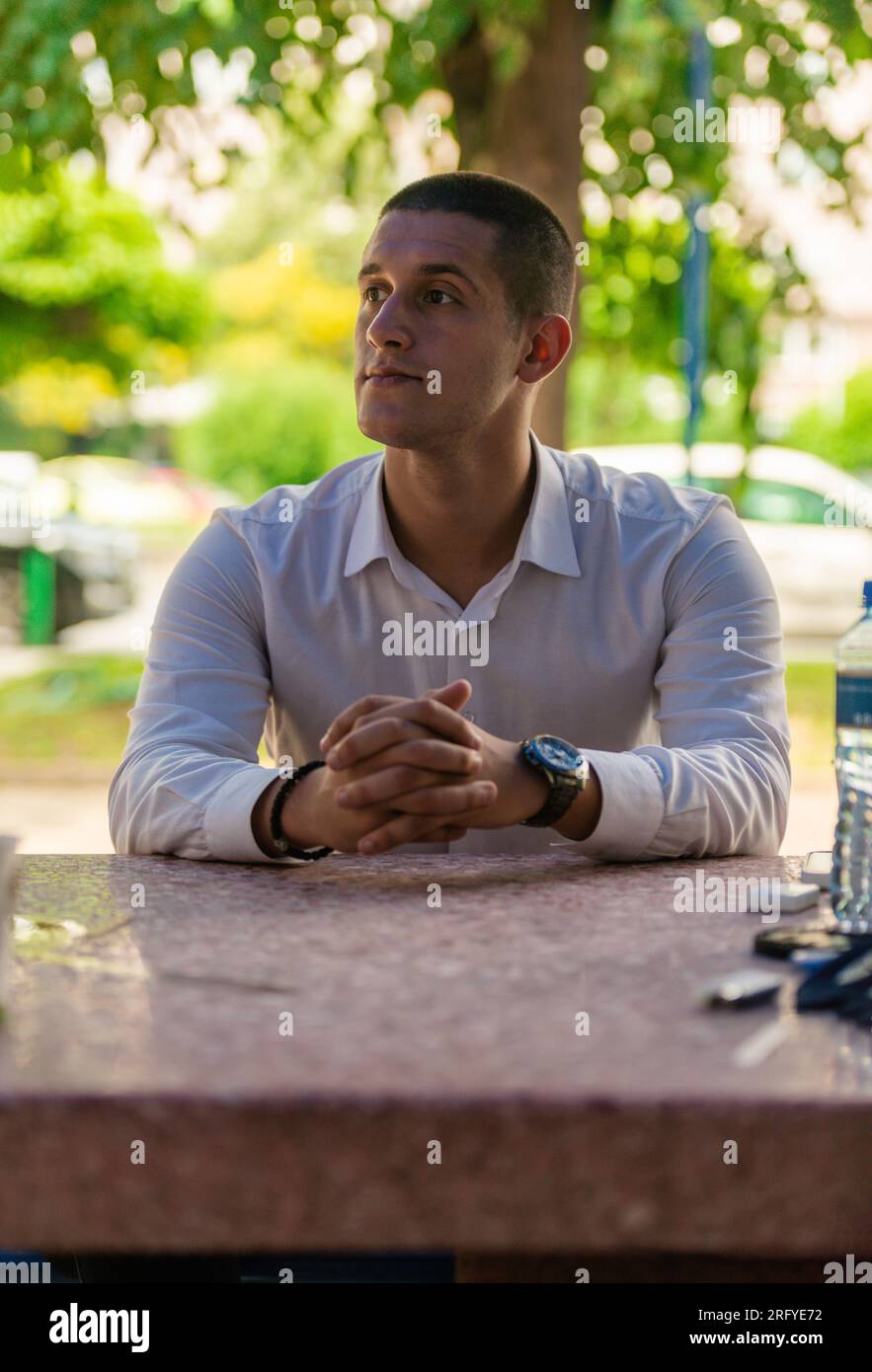 Portrait of a handsome, confident and well- dressed man sitting down ...