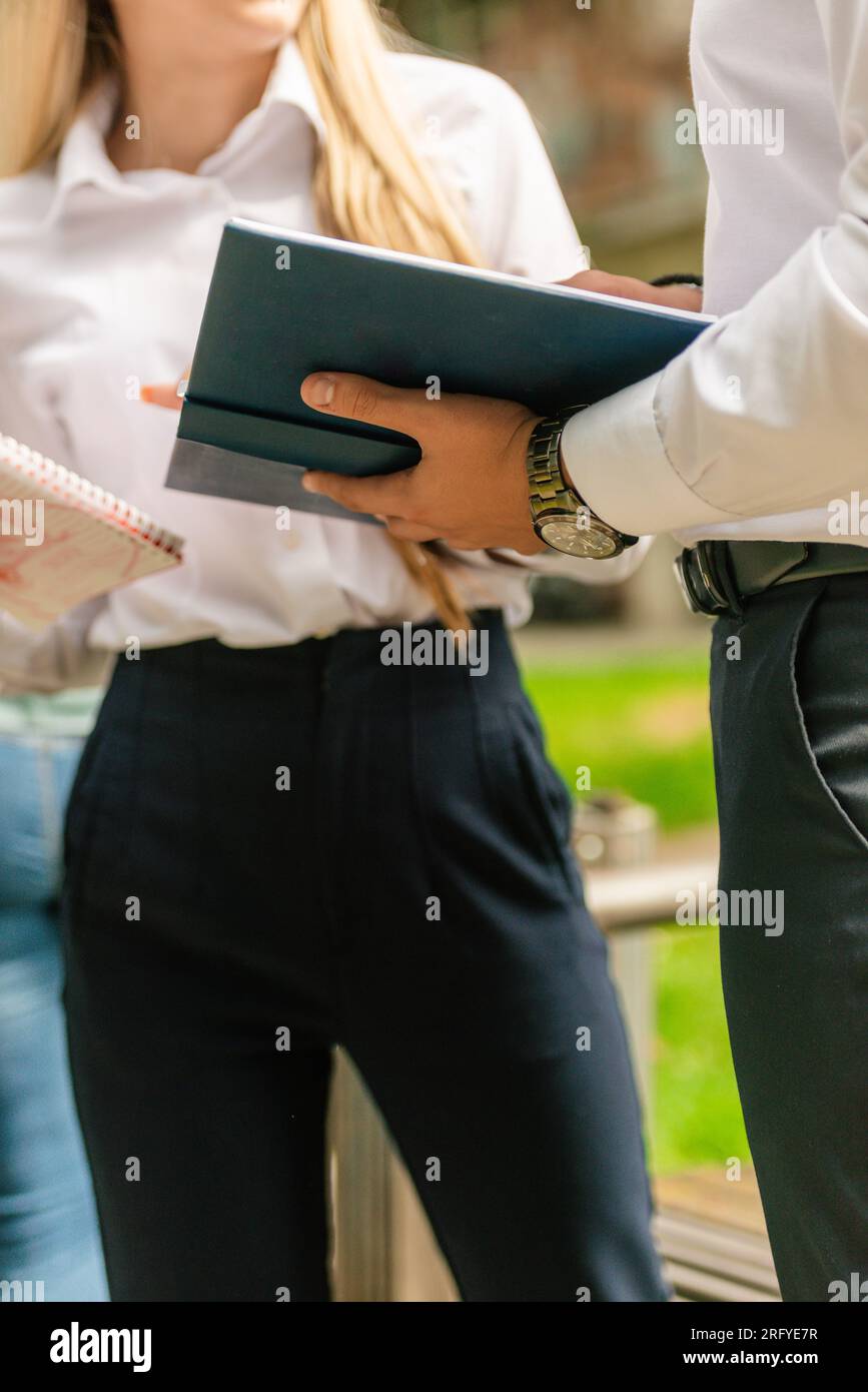 Closeup of two well-dressed students standing outside with notebooks in ...