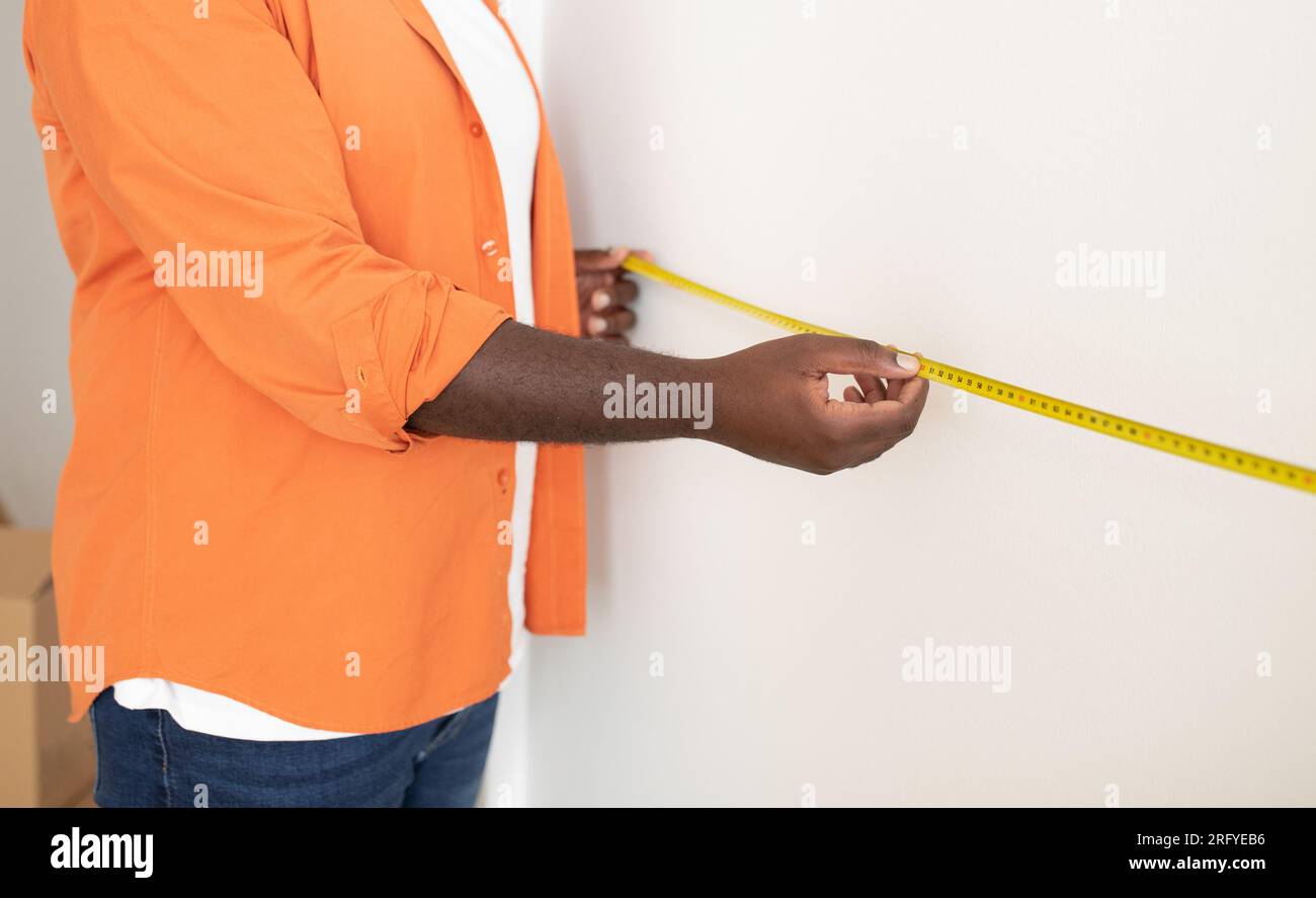 Black Man Taking Measurements With Tape Ruler On White Wall Indoors ...