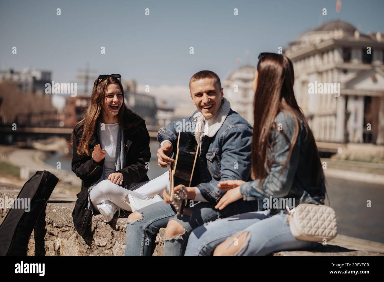 Close up of handsome man playing guitar and laughing with his friends ...
