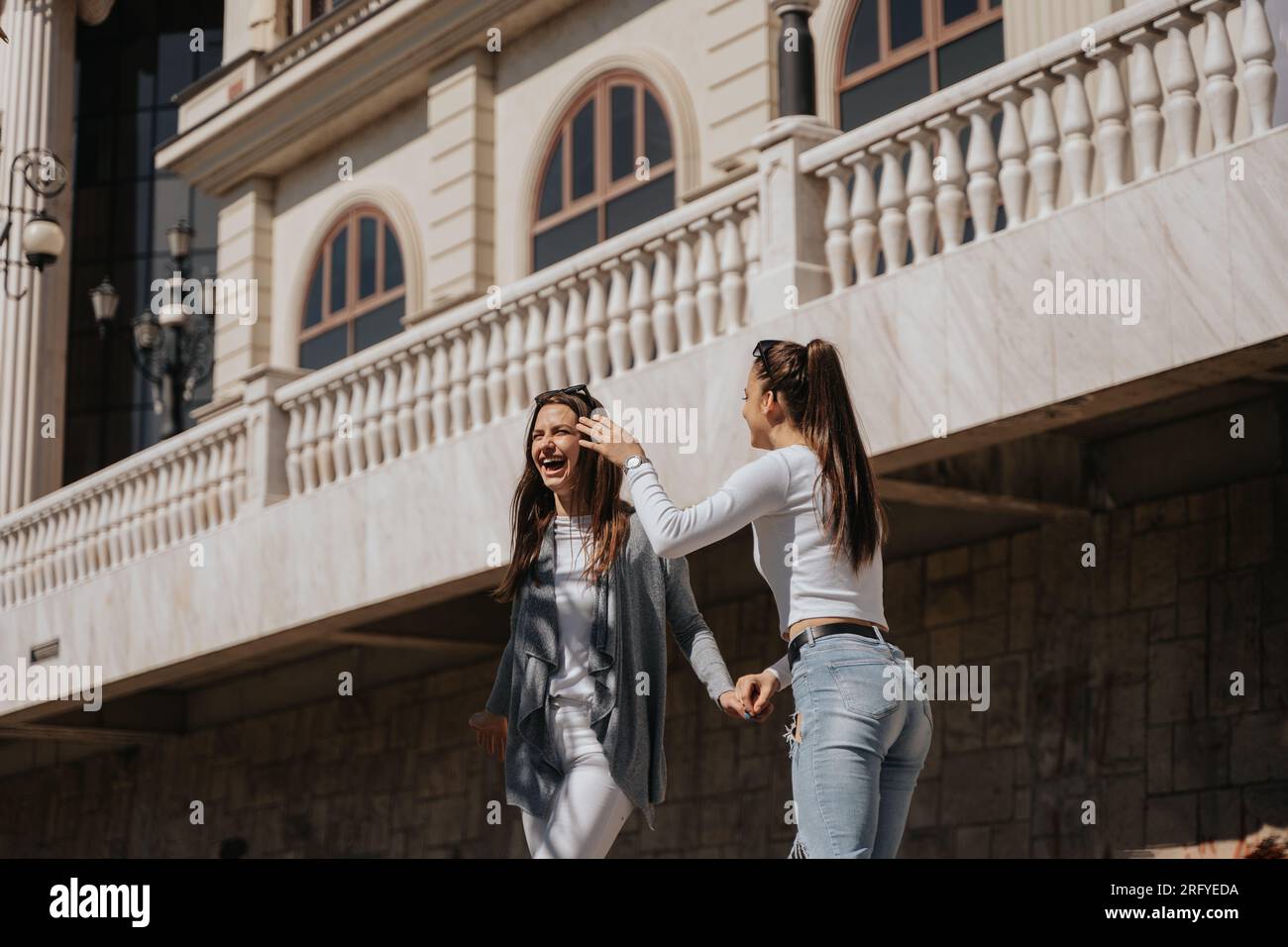 Two beautiful brunette girls laughing while standing in front of the ...
