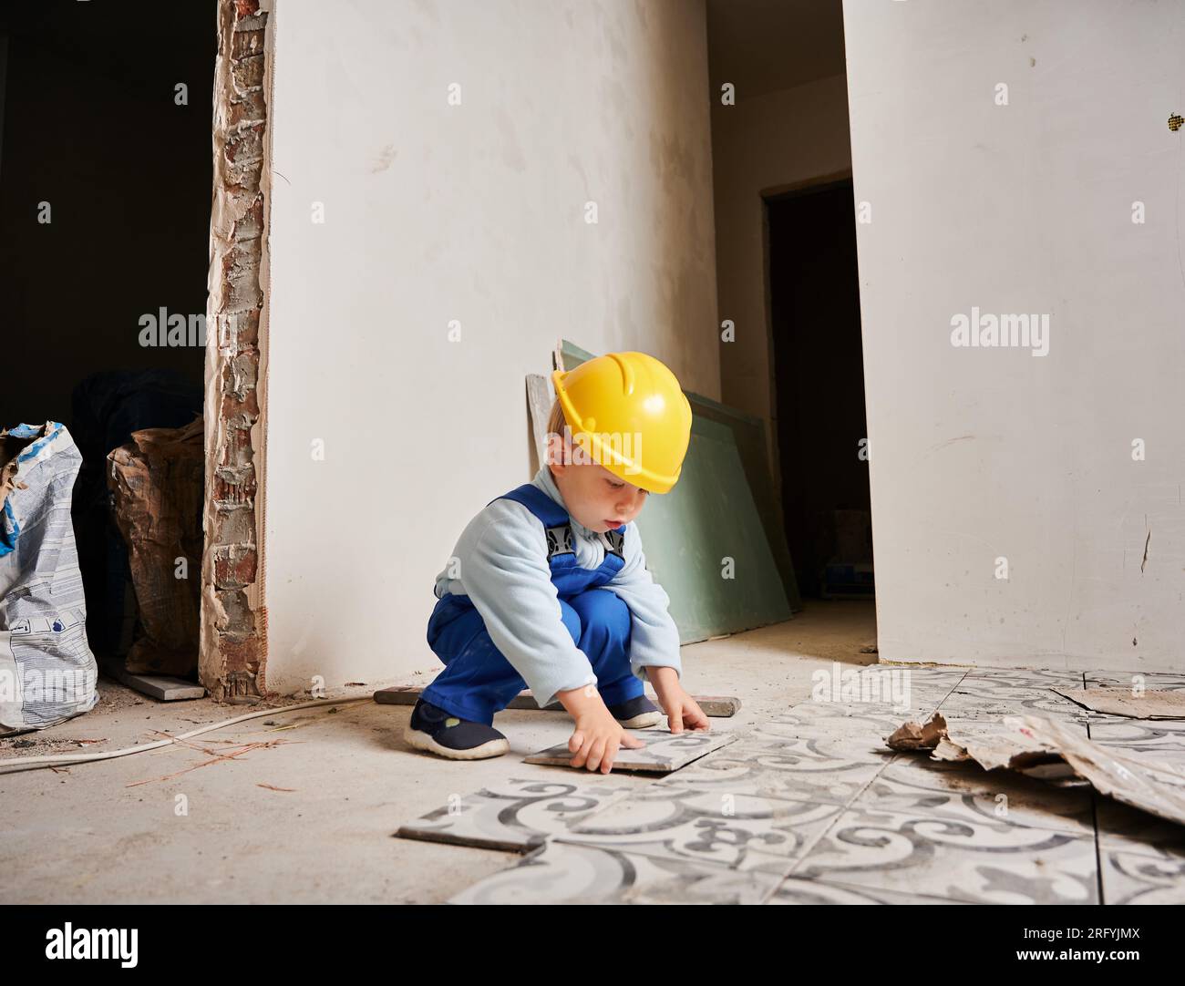 Little boy construction worker installing ceramic tile on the floor in ...