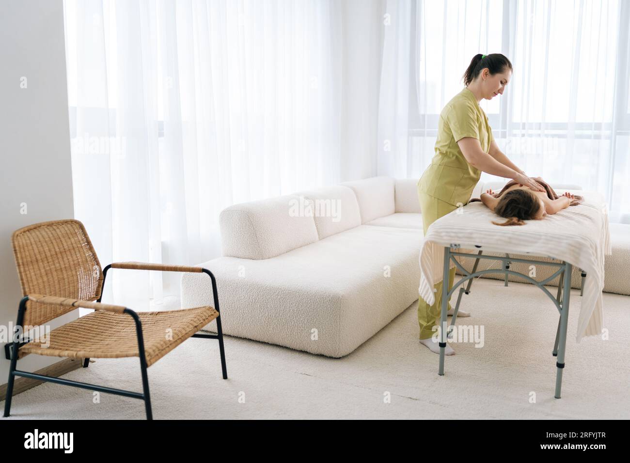 Remote wide shot of female masseuse doing back and lumbar region ...