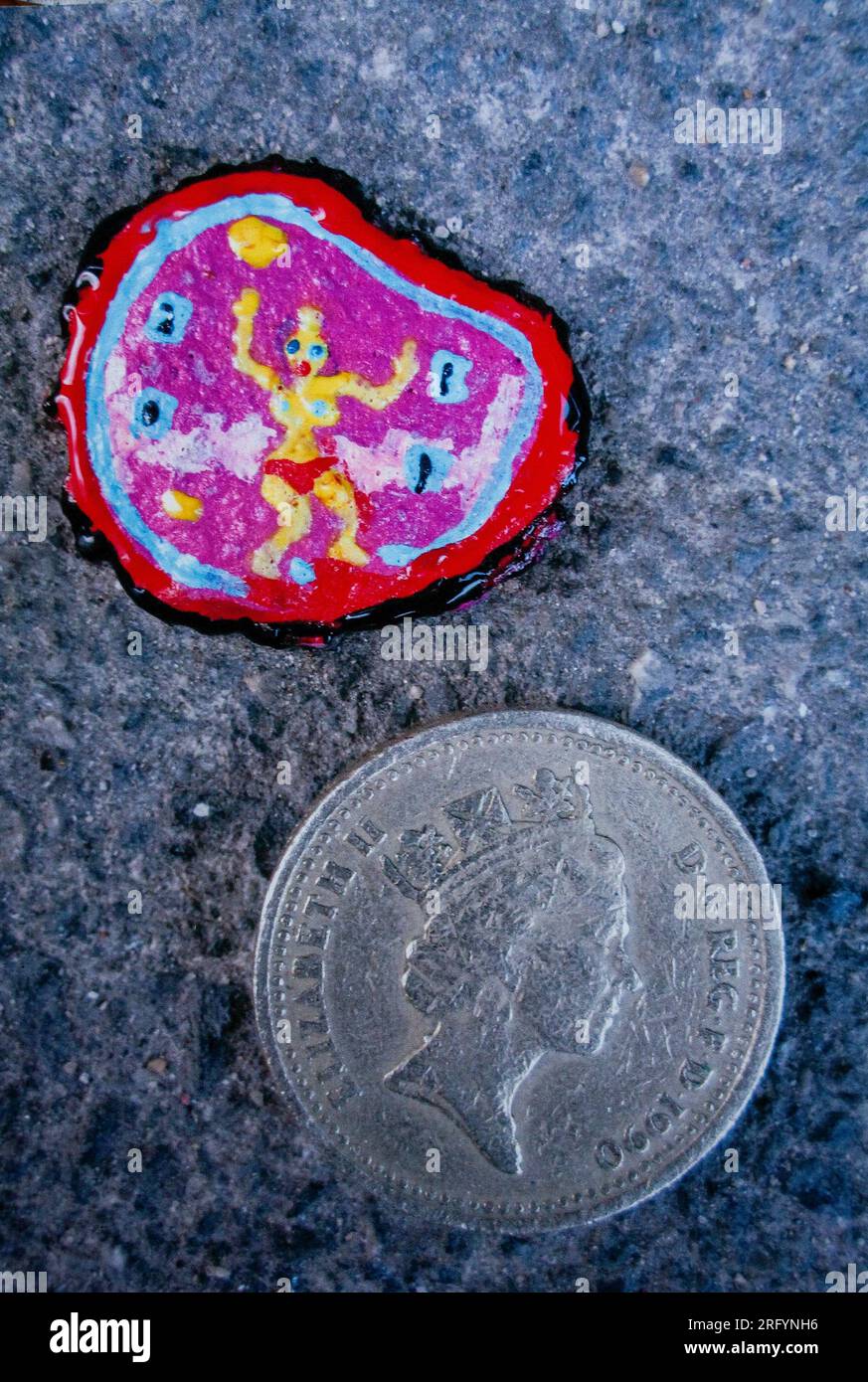 London, UK. Tiny work of art painted on a discarded piece of chewing ...