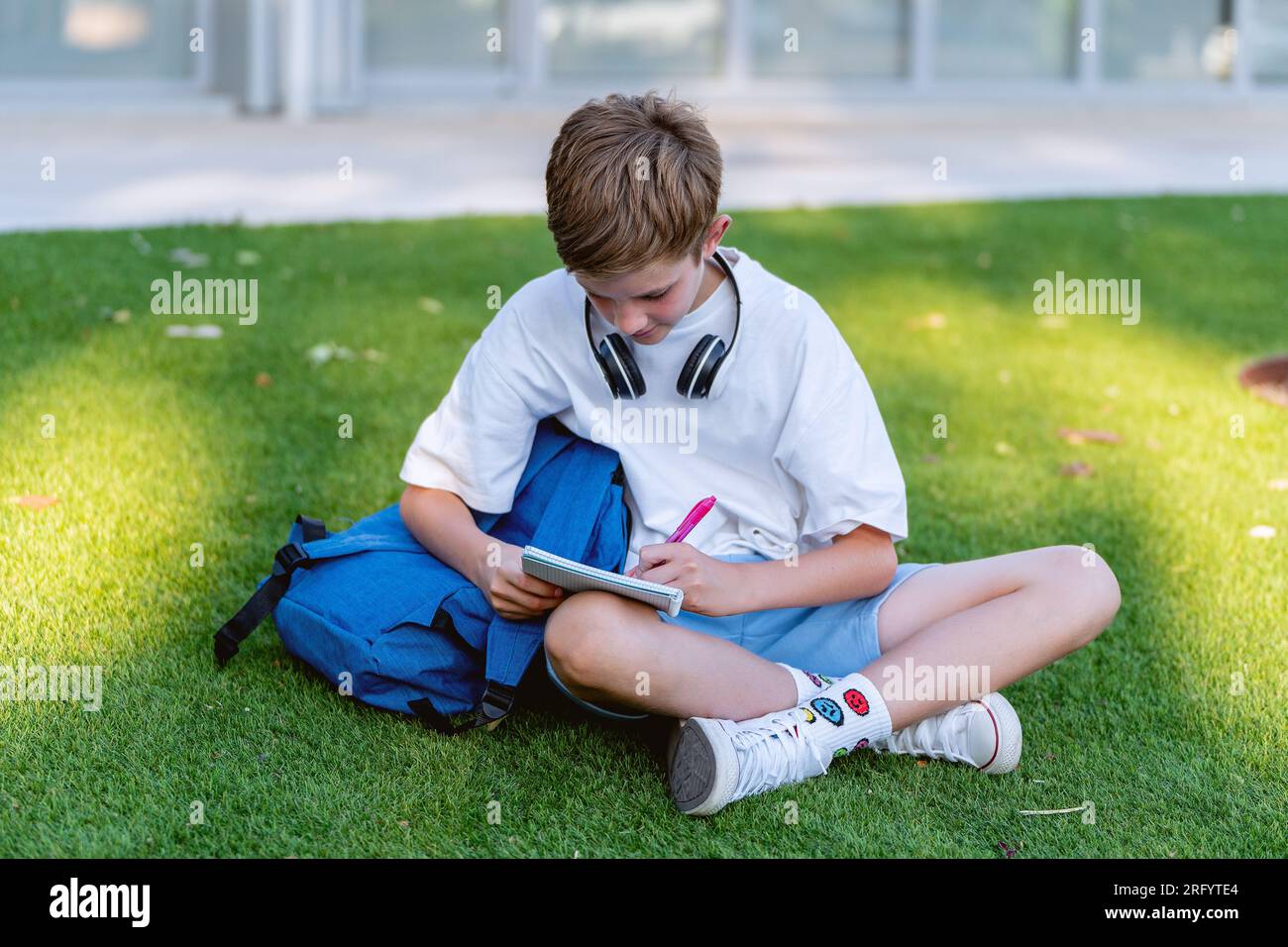 Teenage boy doing school homework with a notebook while sitting on the ...