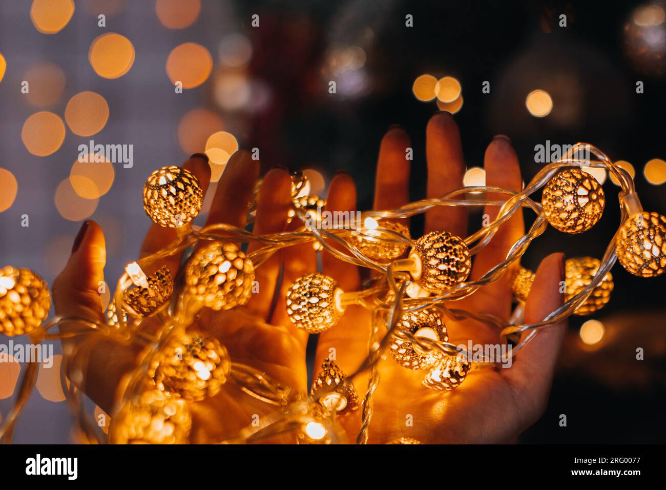 Female hands holding golden Christmas magic garland against a ...