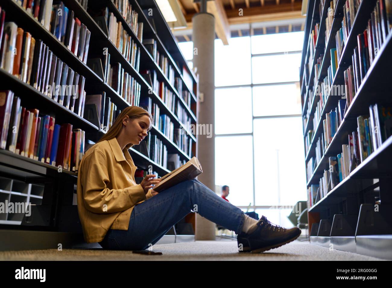 Smart girl student holding book sitting in university library or ...