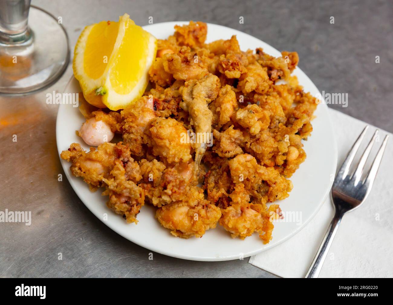 Battered fried baby squid with lemon Stock Photo - Alamy