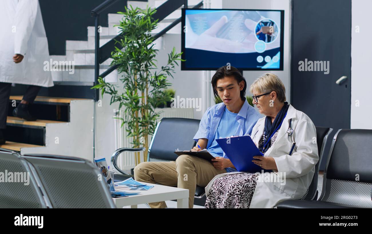 Doctor helping patient to fill medical files during checkup visit ...