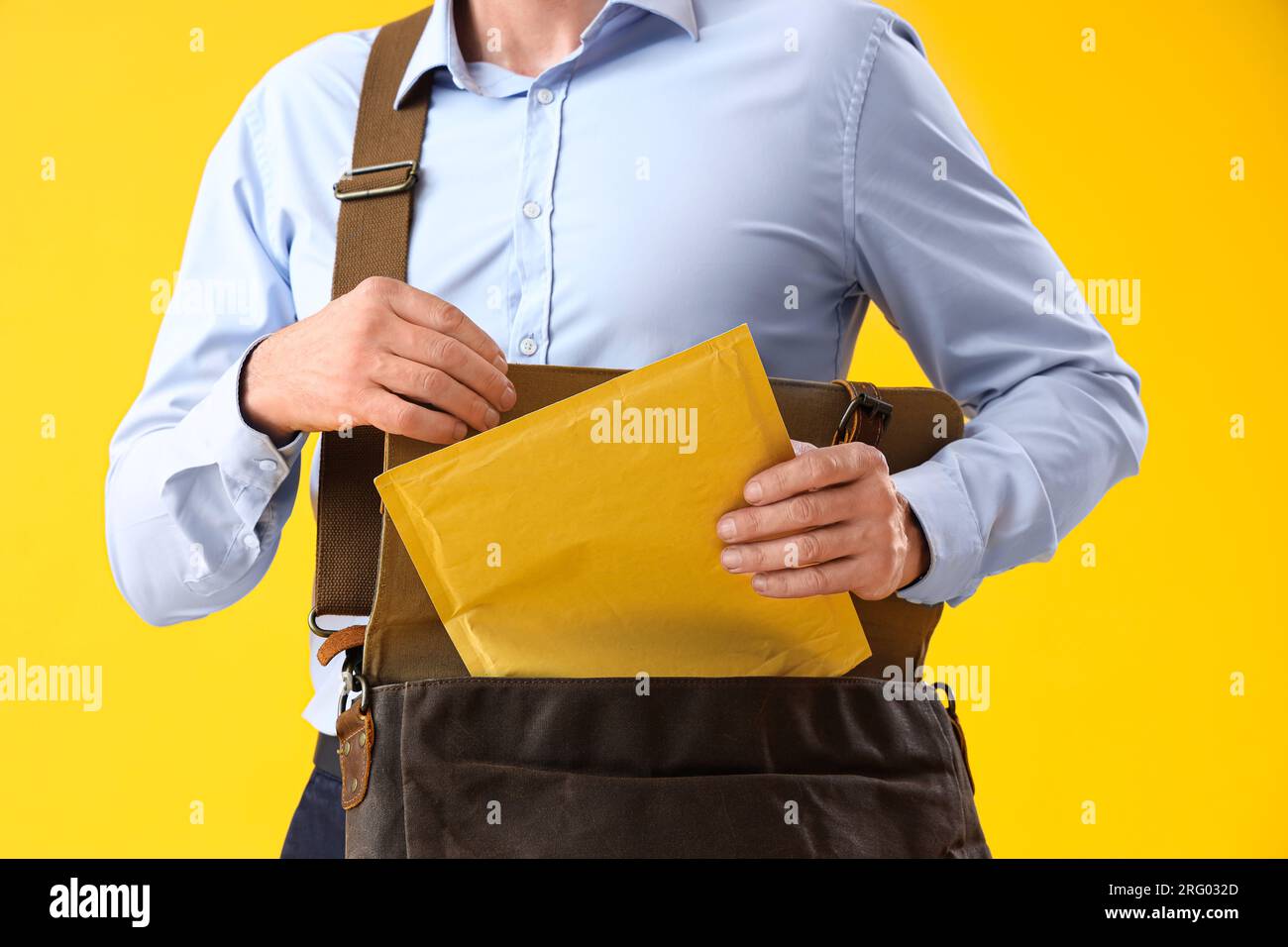 Mature postman with bag and envelope on yellow background, closeup ...