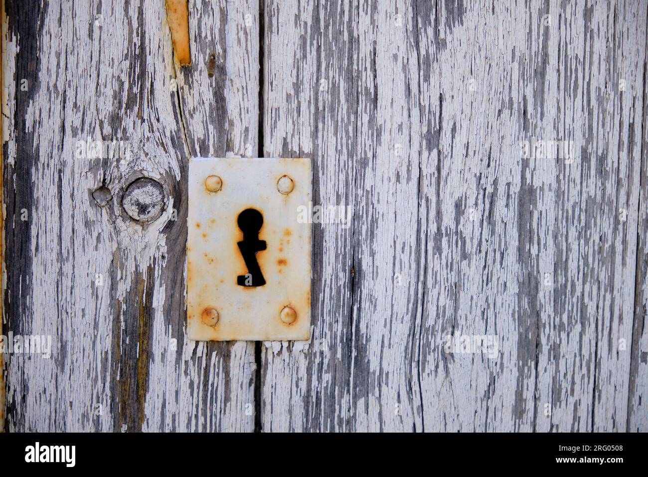 Old metal rustic door keyhole in Z shape on a grey wooded door close up ...