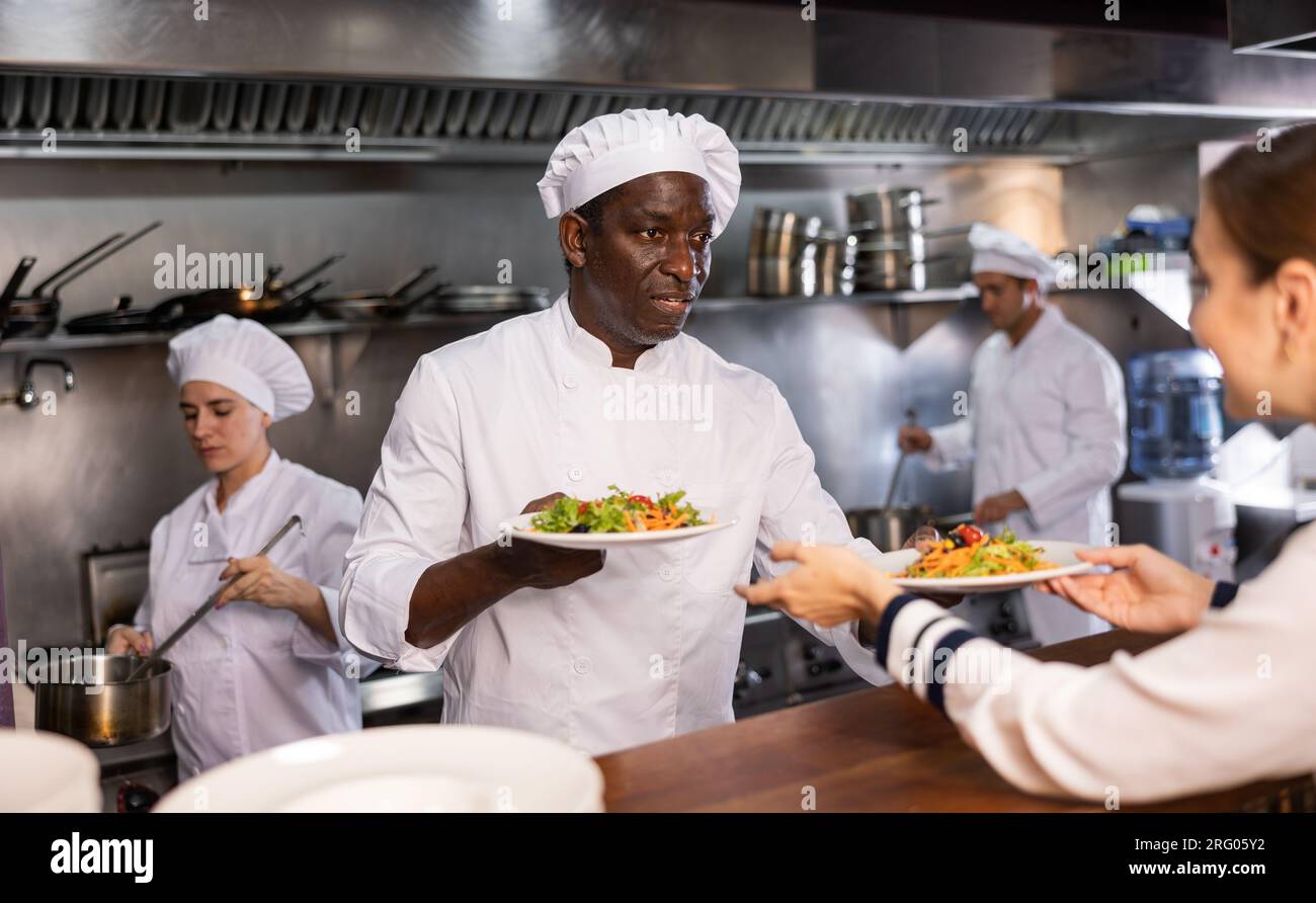 Chef giving out ready salads to waitress Stock Photo - Alamy