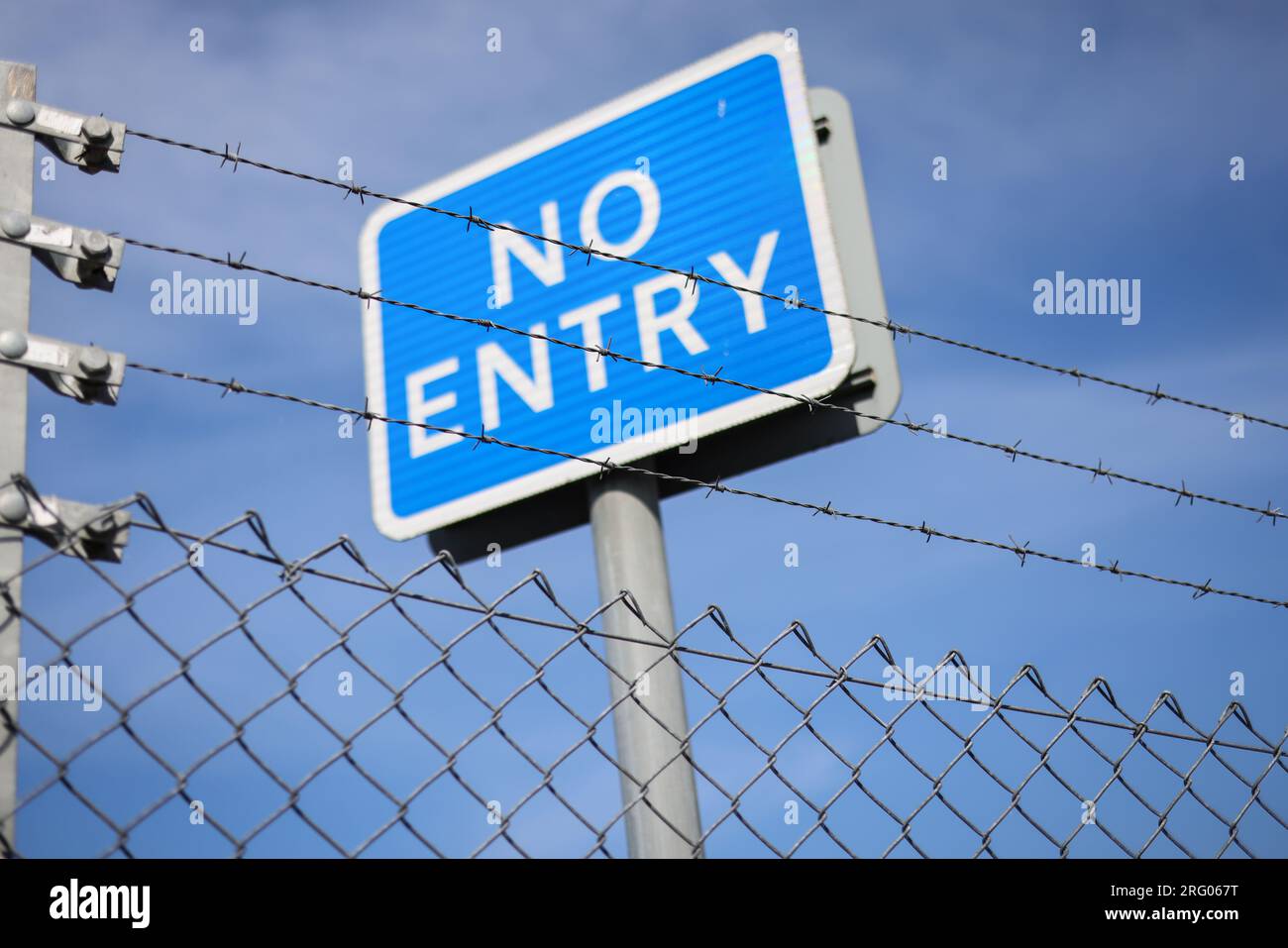 A 'no entry' sign, blue background and white text. The sign is behind ...