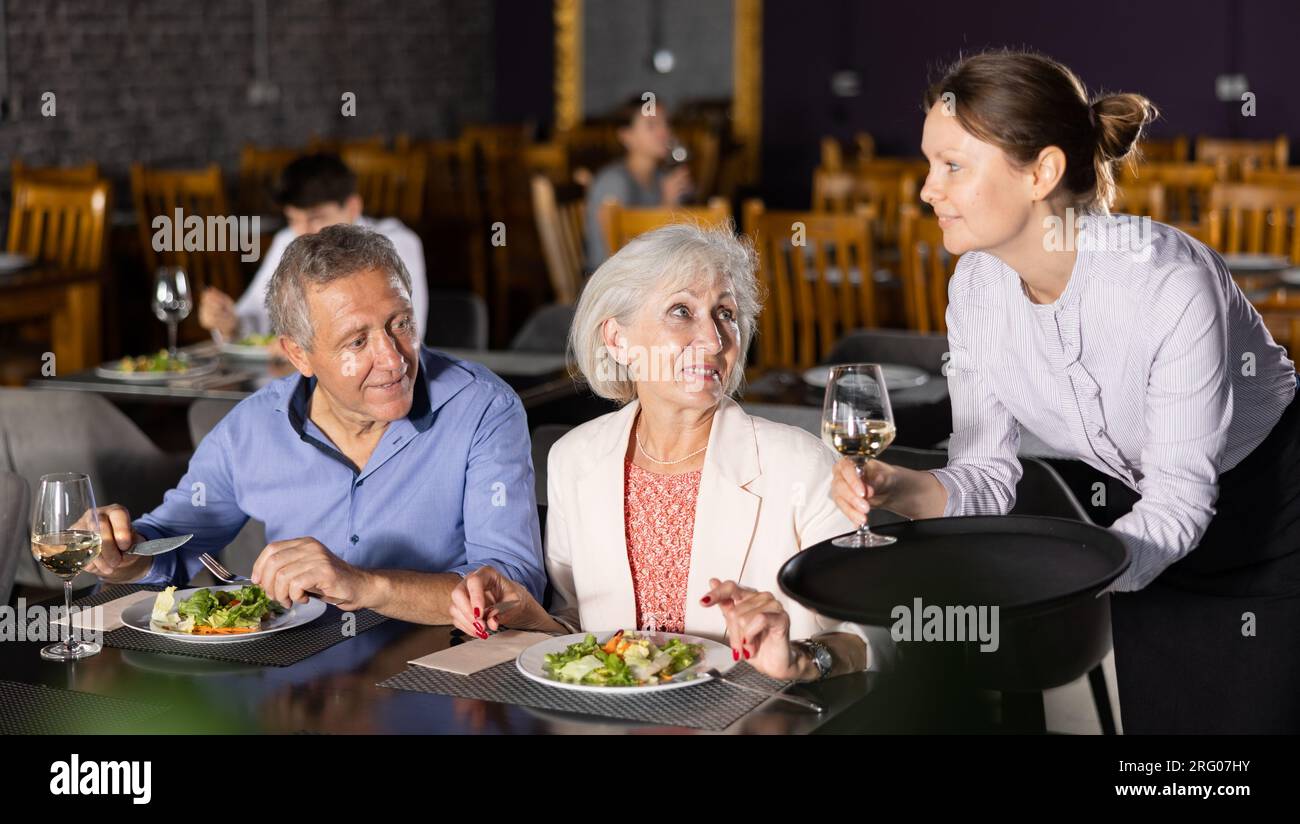 Female hostess serves puts on table order for elderly spouses Stock ...