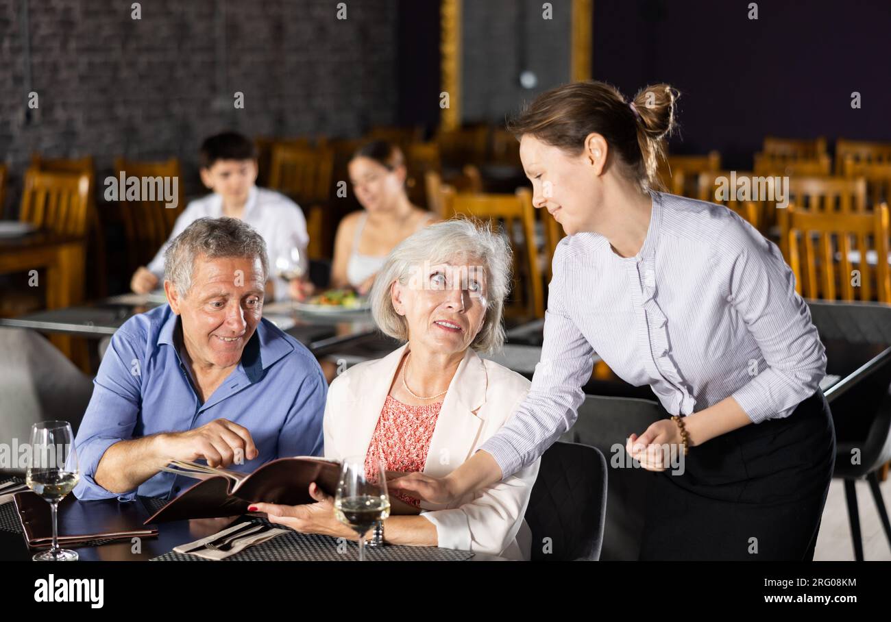 Woman waiter taking order from elderly couple in restaurant Stock Photo ...