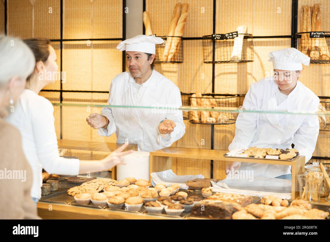 Happy male and female bakery workers showing around their workplace ...