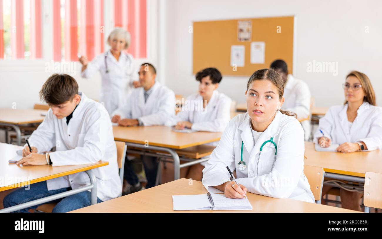Doctors different age sitting at desk in classroom working during ...