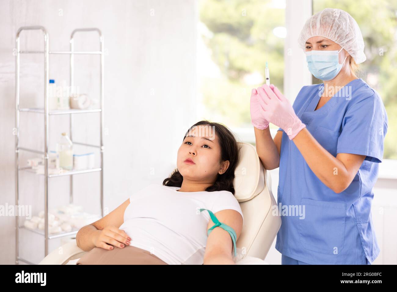 Female anesthesiologist injecting anesthetic into a vein on her arm ...