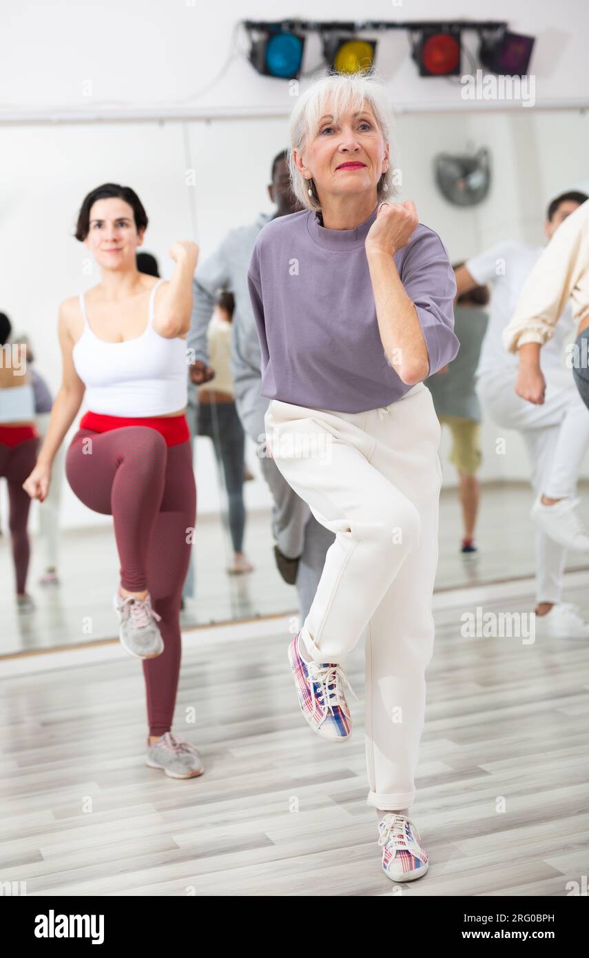Cheerful old lady learning new modern dance in group dance lesson Stock ...