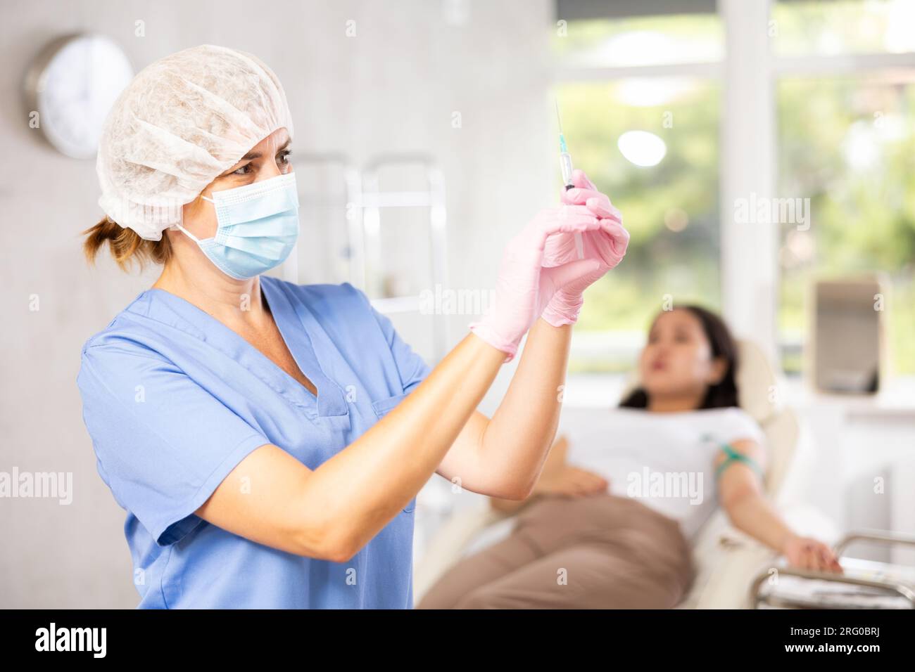 Female anesthesiologist injecting anesthetic into a vein on her arm ...
