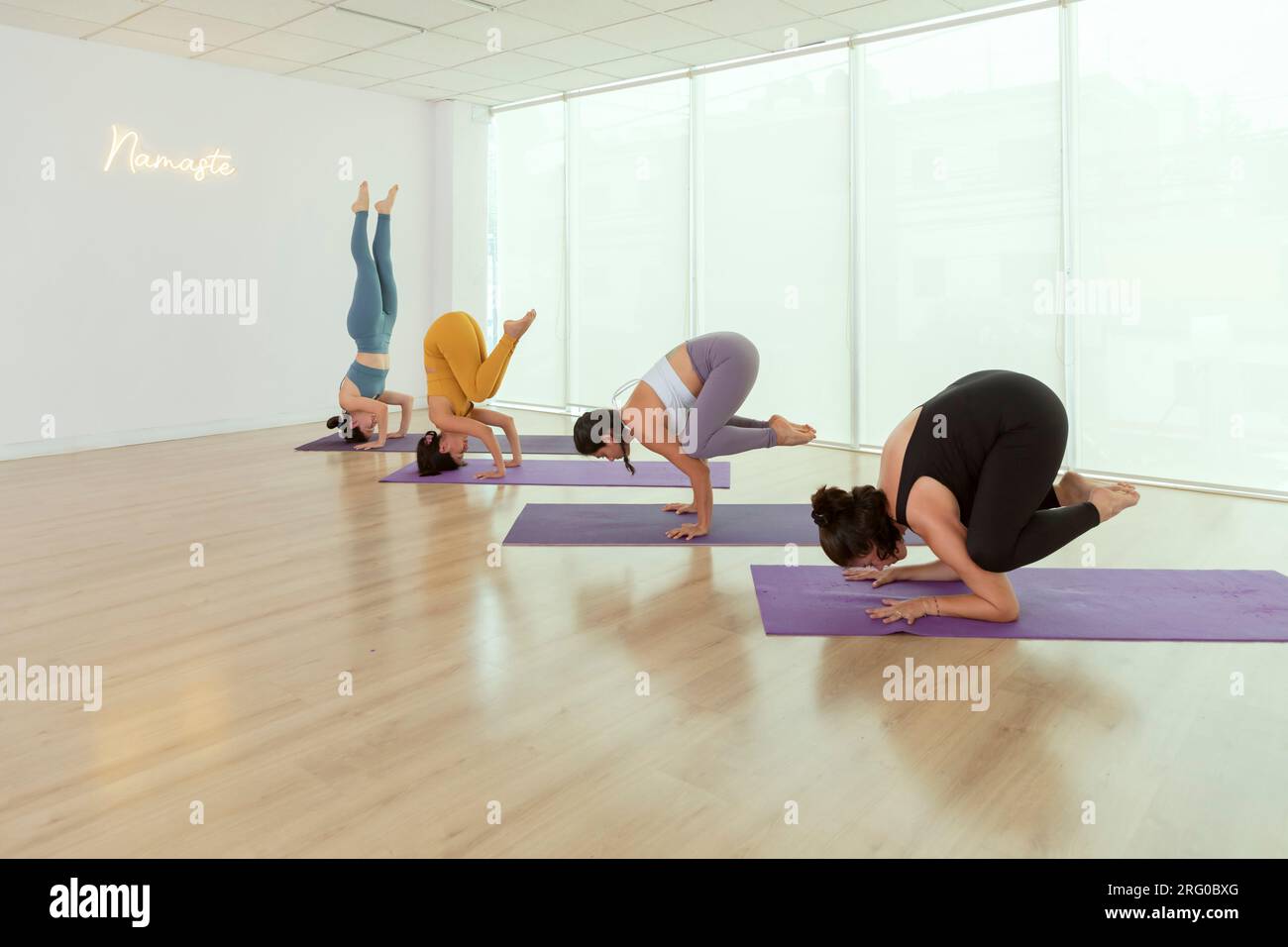 Four women do the progression of a yoga pose inside a studio, with copy ...