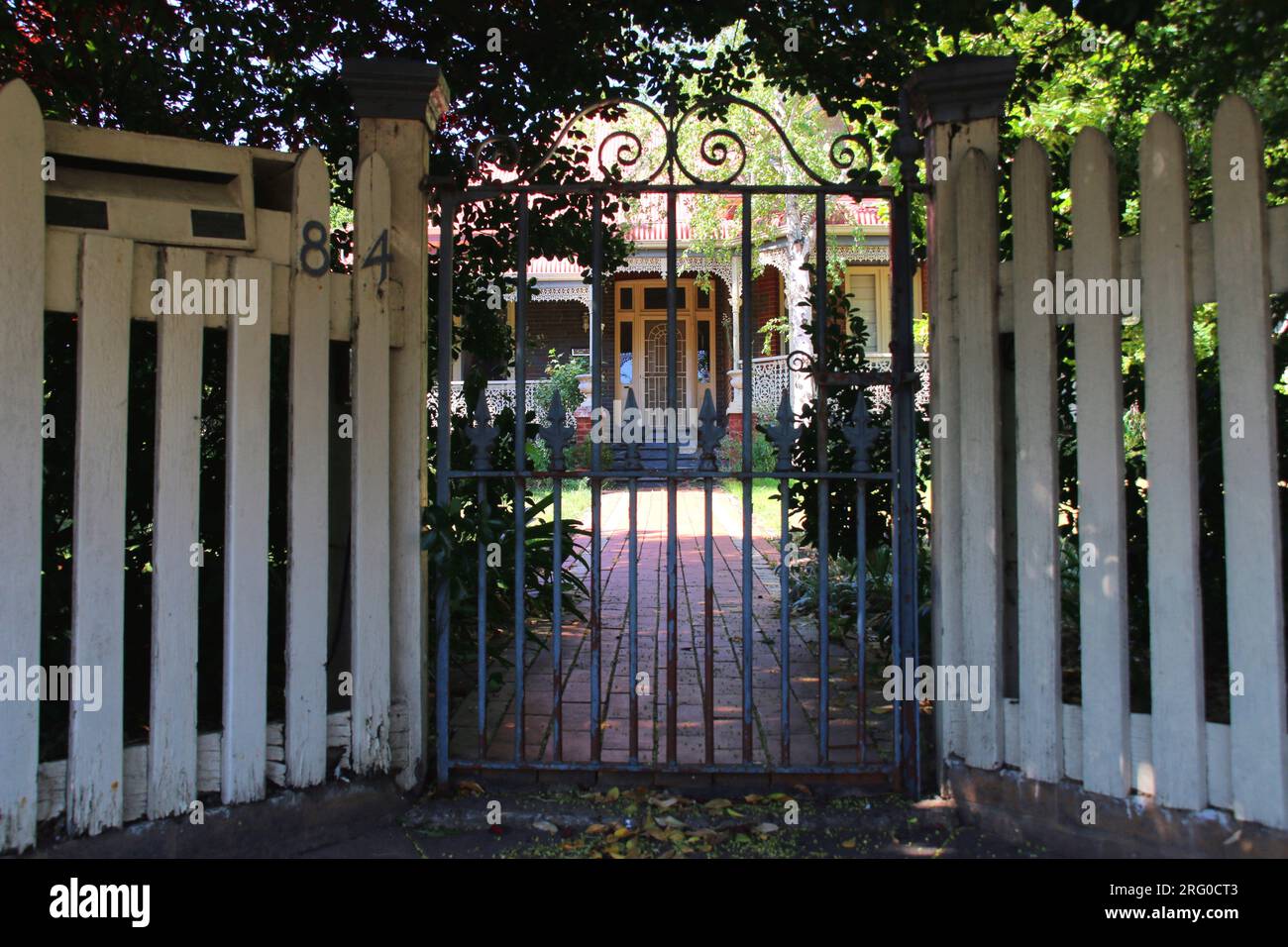 A wrought iron gate and white picket fence frame the entry to the ...