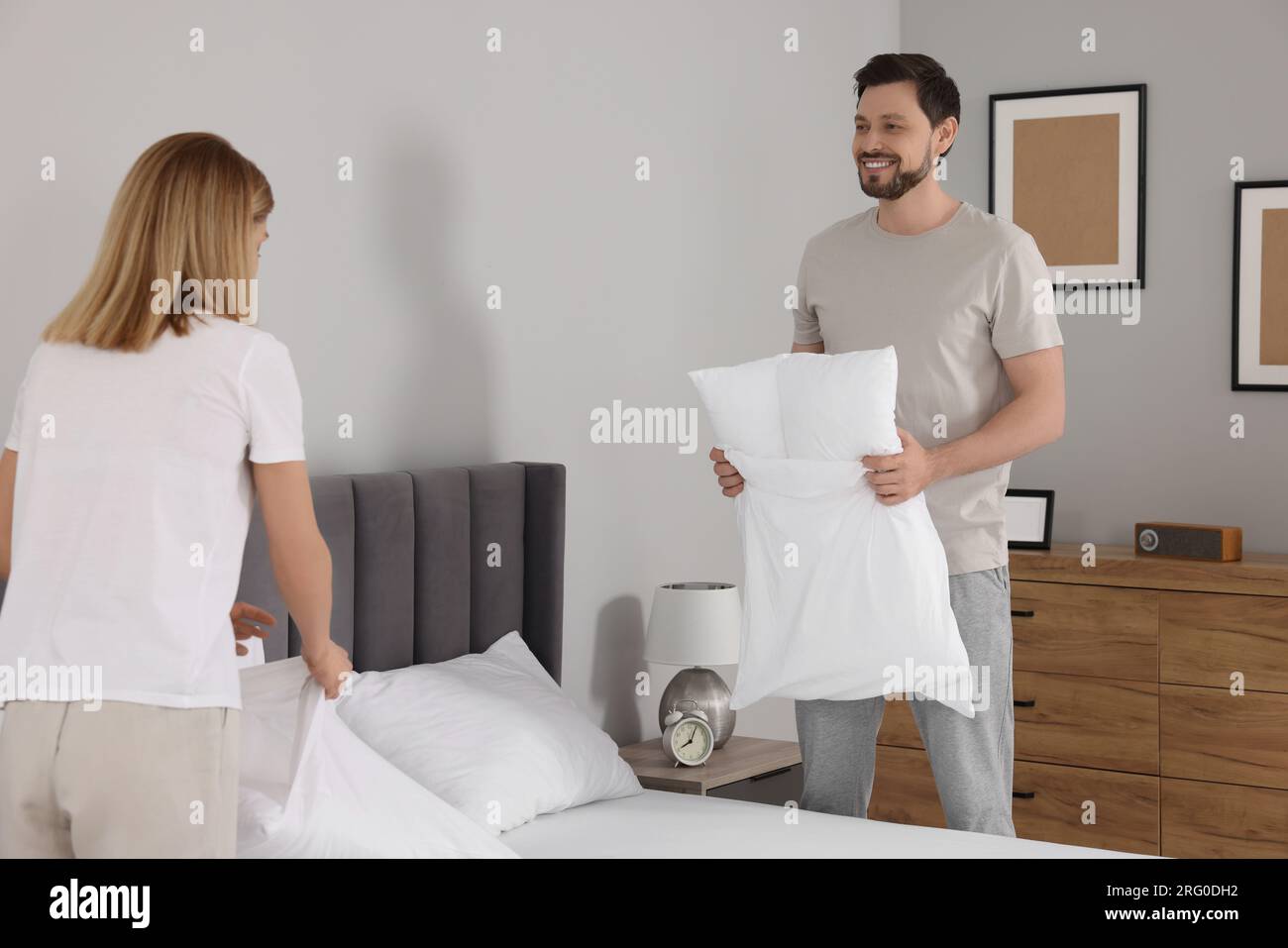 Couple changing bed linens in room. Domestic chores Stock Photo - Alamy