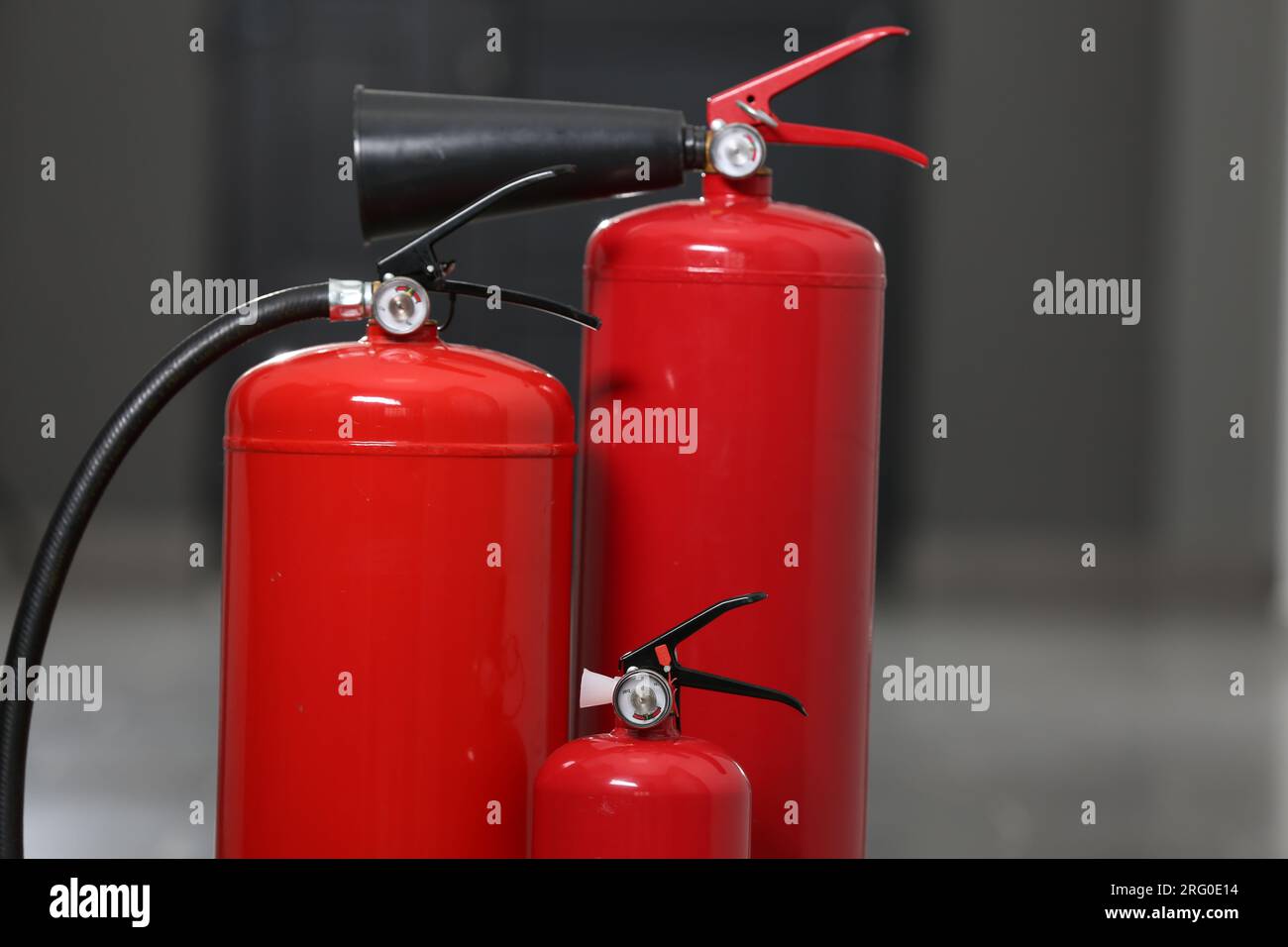 Three new red fire extinguishers in hall, closeup. Space for text Stock ...
