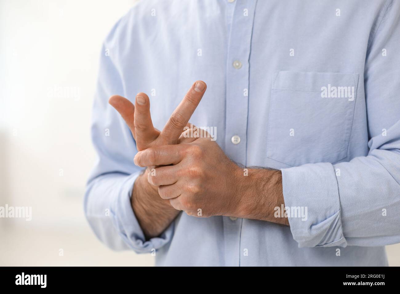 Man cracking his knuckles on blurred background, closeup. Bad habit ...