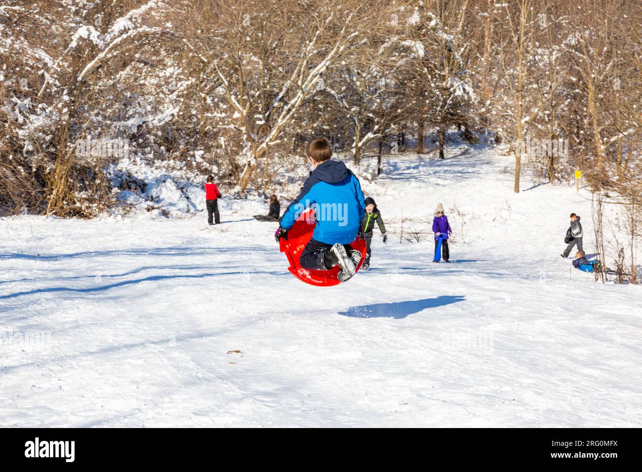 A young boy casts a shadow as he goes airborne while sledding down a hill at Metea County Park ...