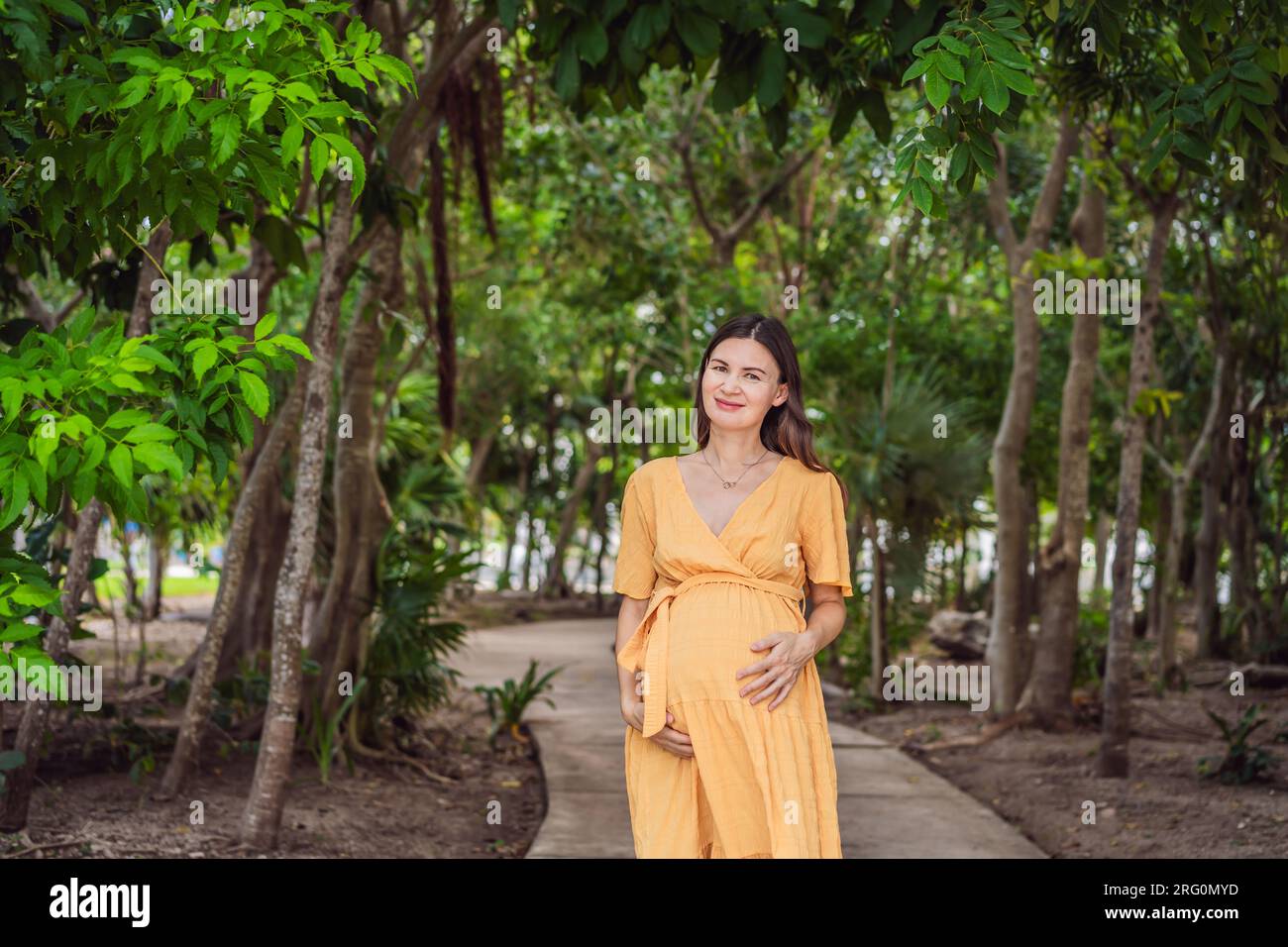 A serene and radiant pregnant woman after 40, surrounded by nature's beauty in the park ...