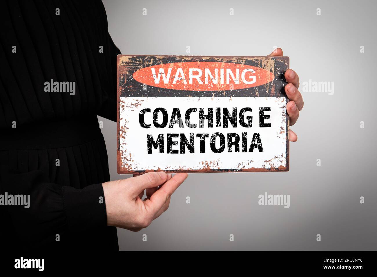 Coaching and Mentoring in Portuguese. A woman is holding a warning sign ...