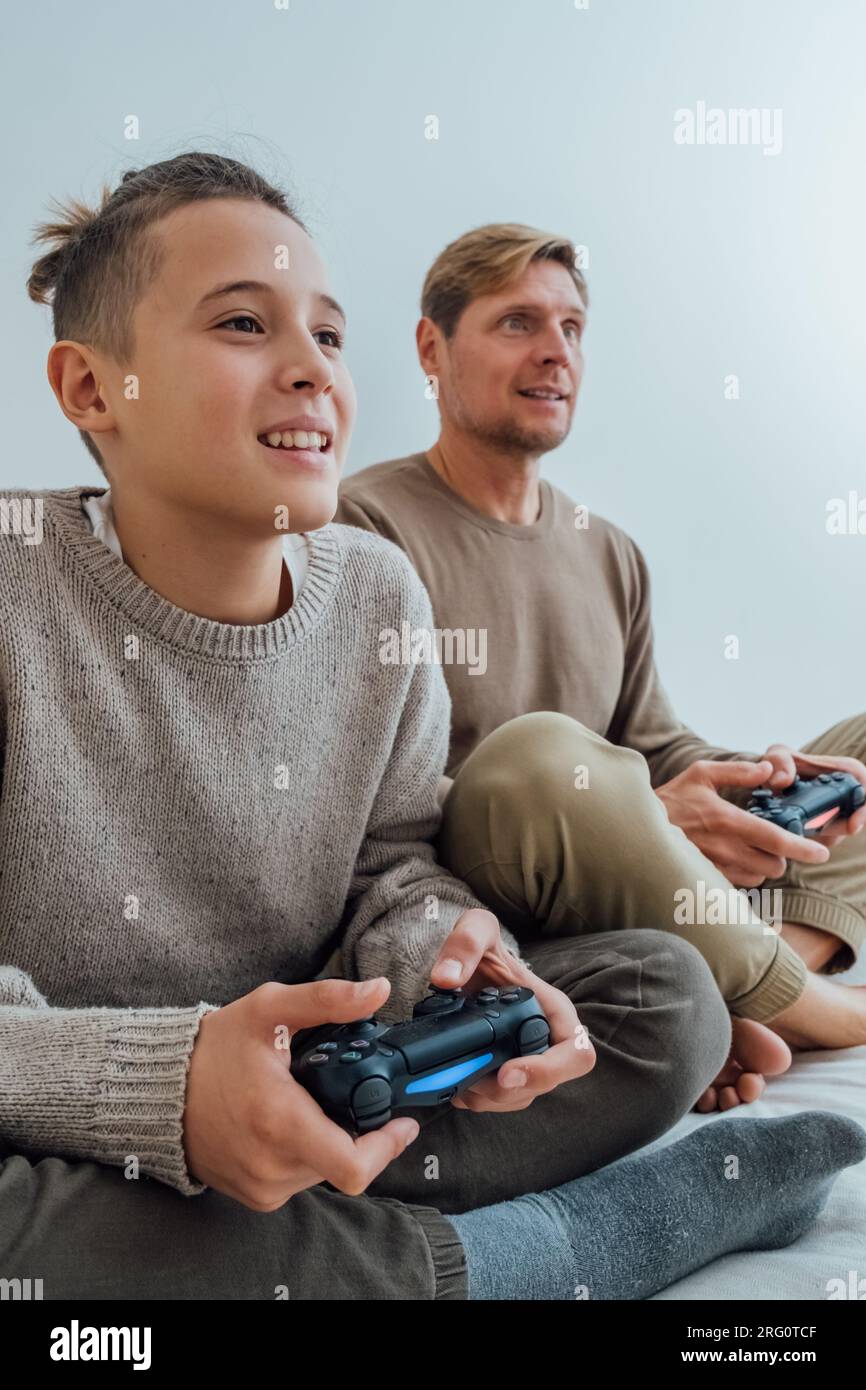 Father with teenage son playing video games on console use joystick ...