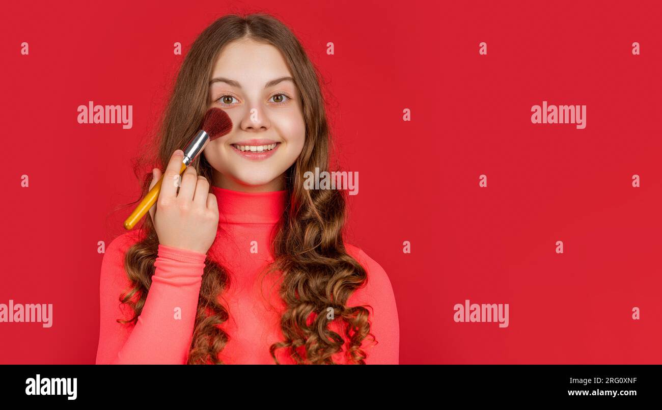 happy child with curly hair apply powder on face with makeup brush ...