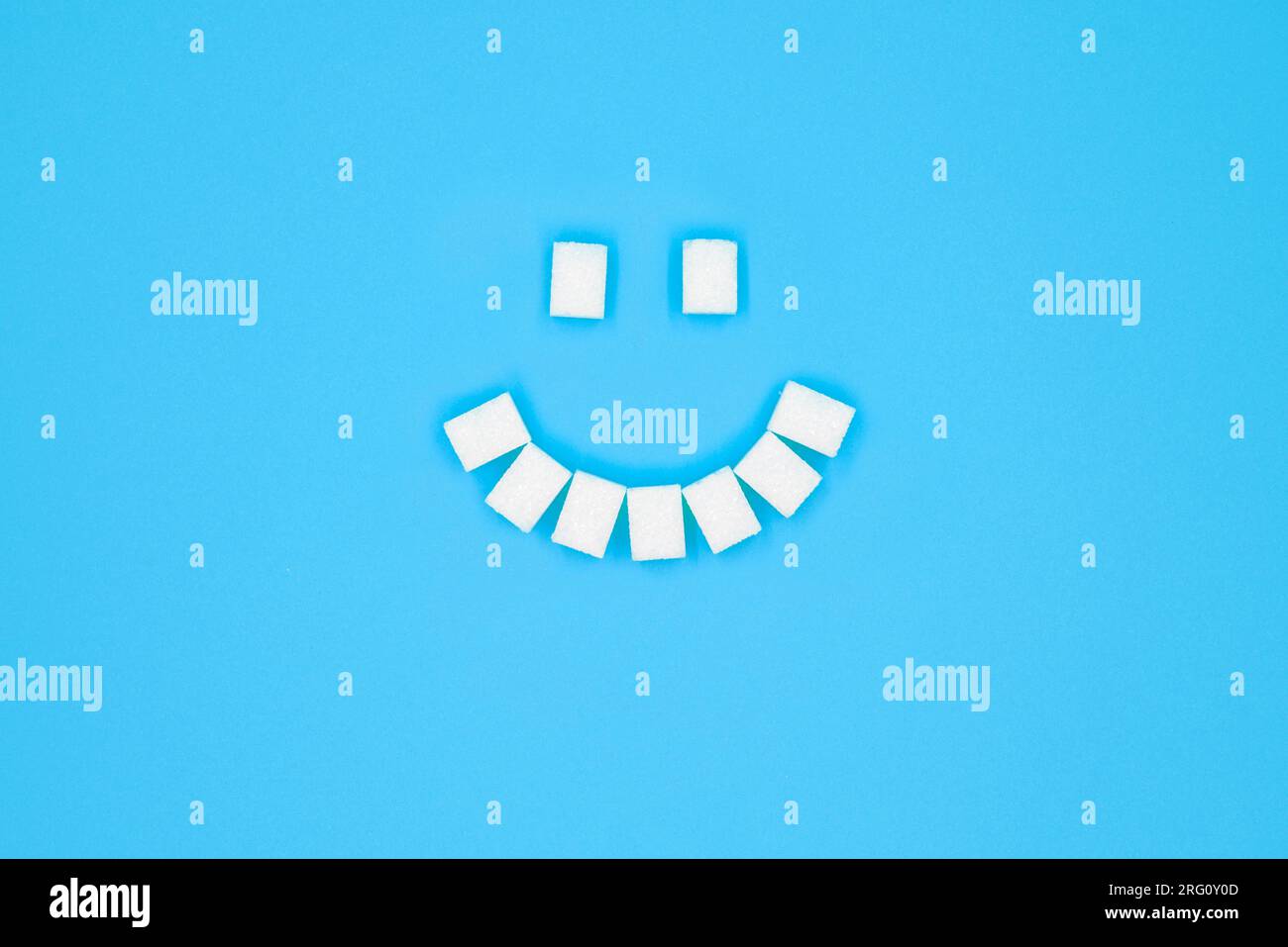 Smile symbol, composed of cubes of sugar on blue background Stock Photo ...